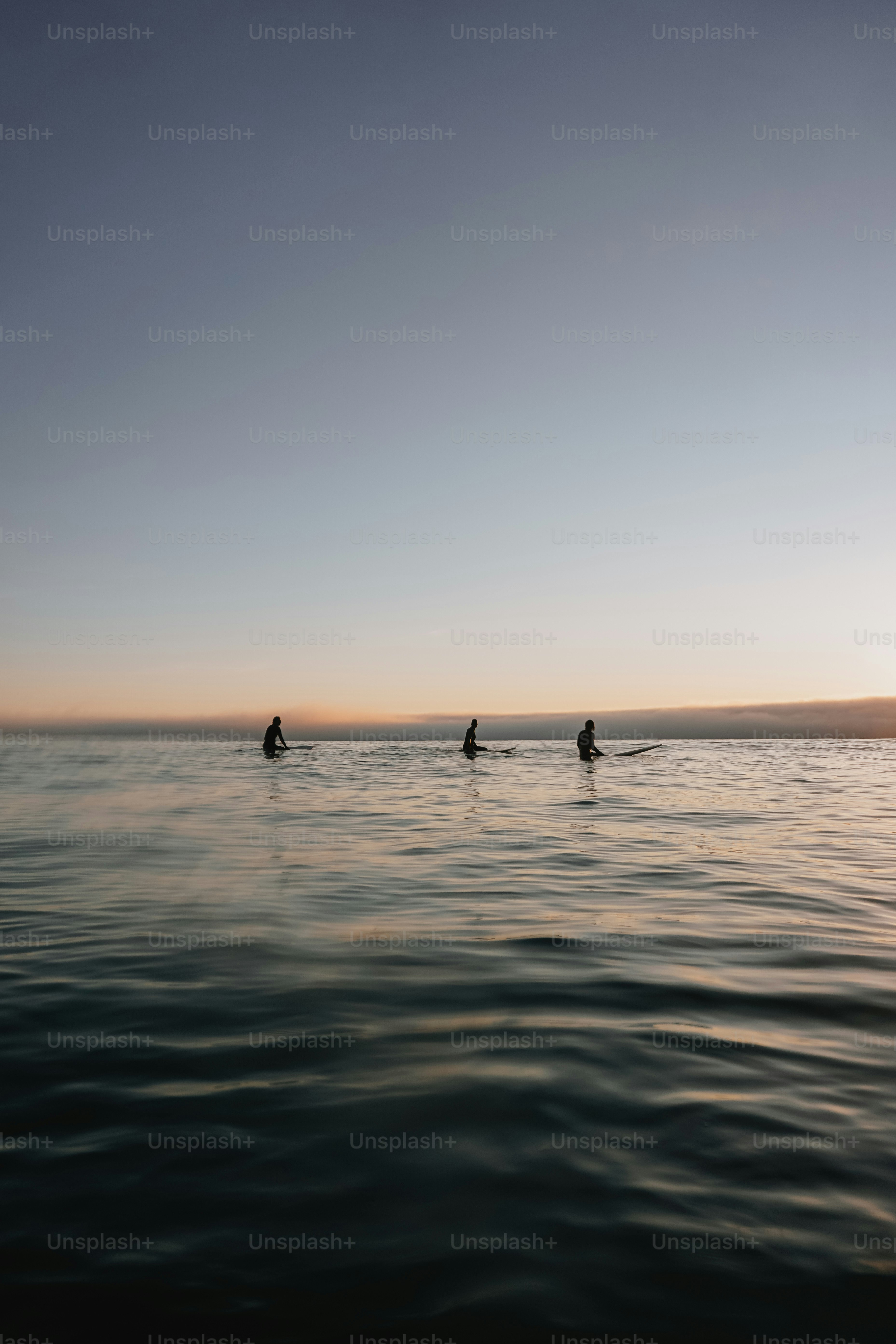 Three surfers wait for waves on the ocean at sunset. photo – Travel ...
