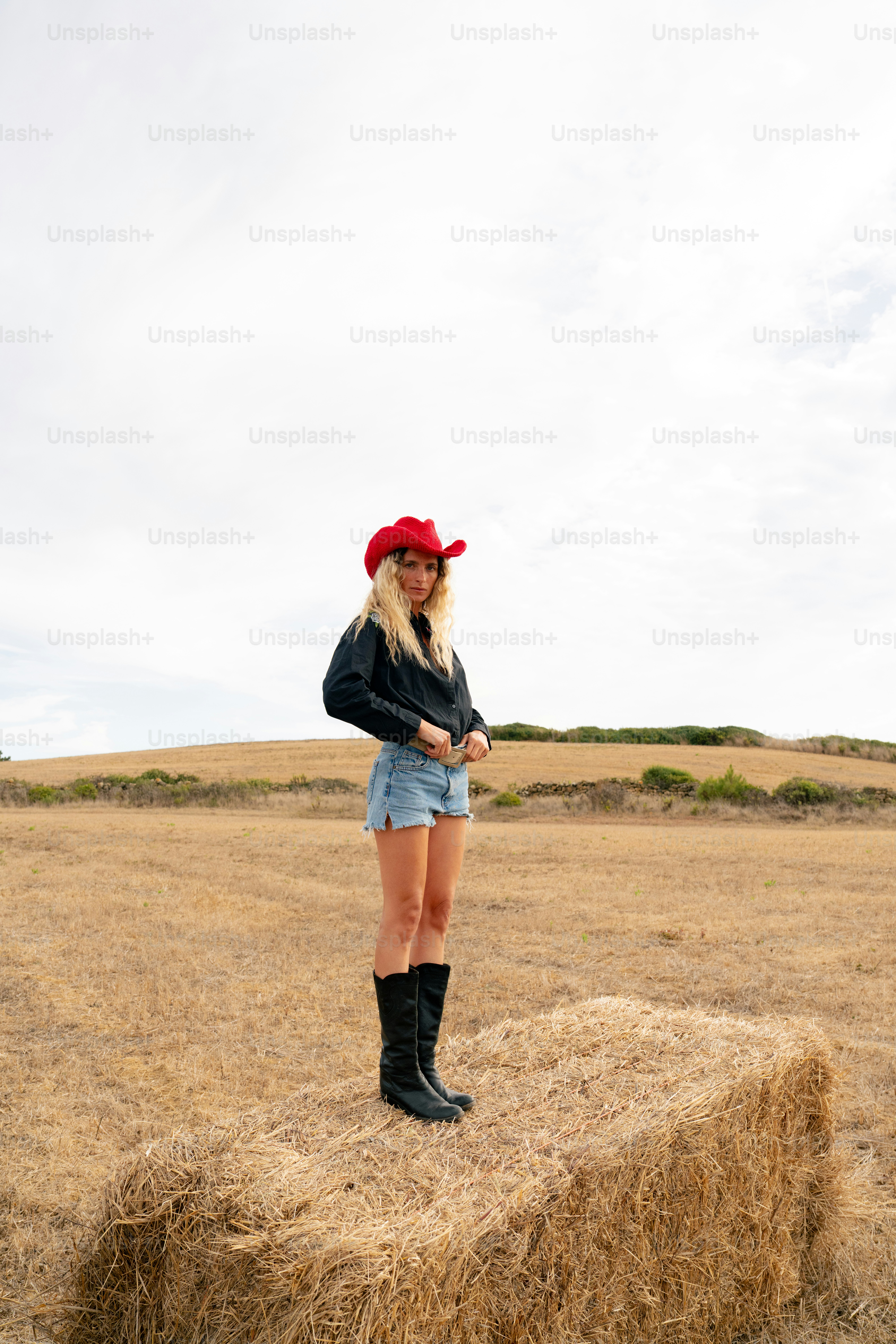 Woman in red cowboy hat squats on hay bale. photo – Woman Image on Unsplash