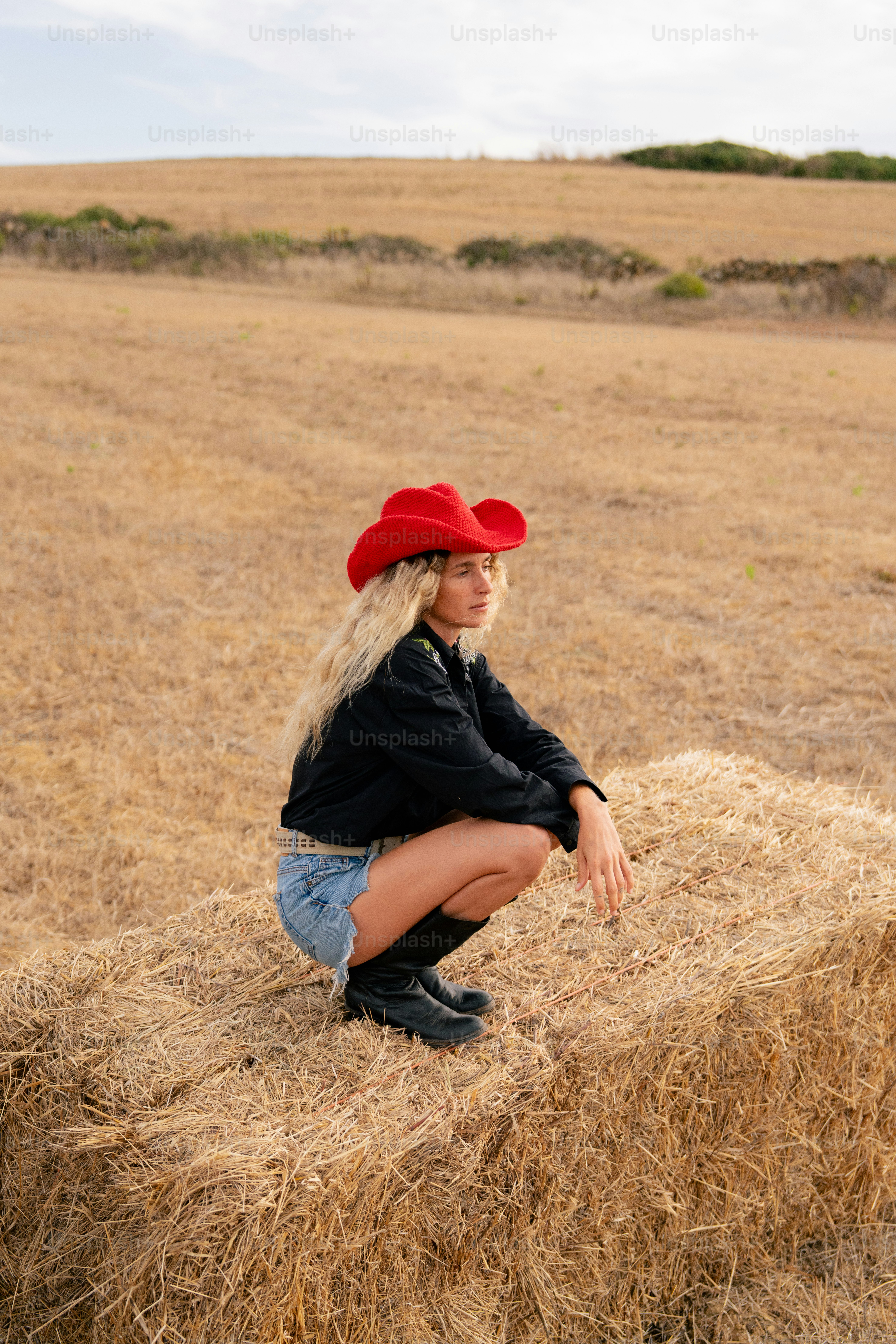 Woman in red cowboy hat squats on hay bale. photo – Woman Image on Unsplash