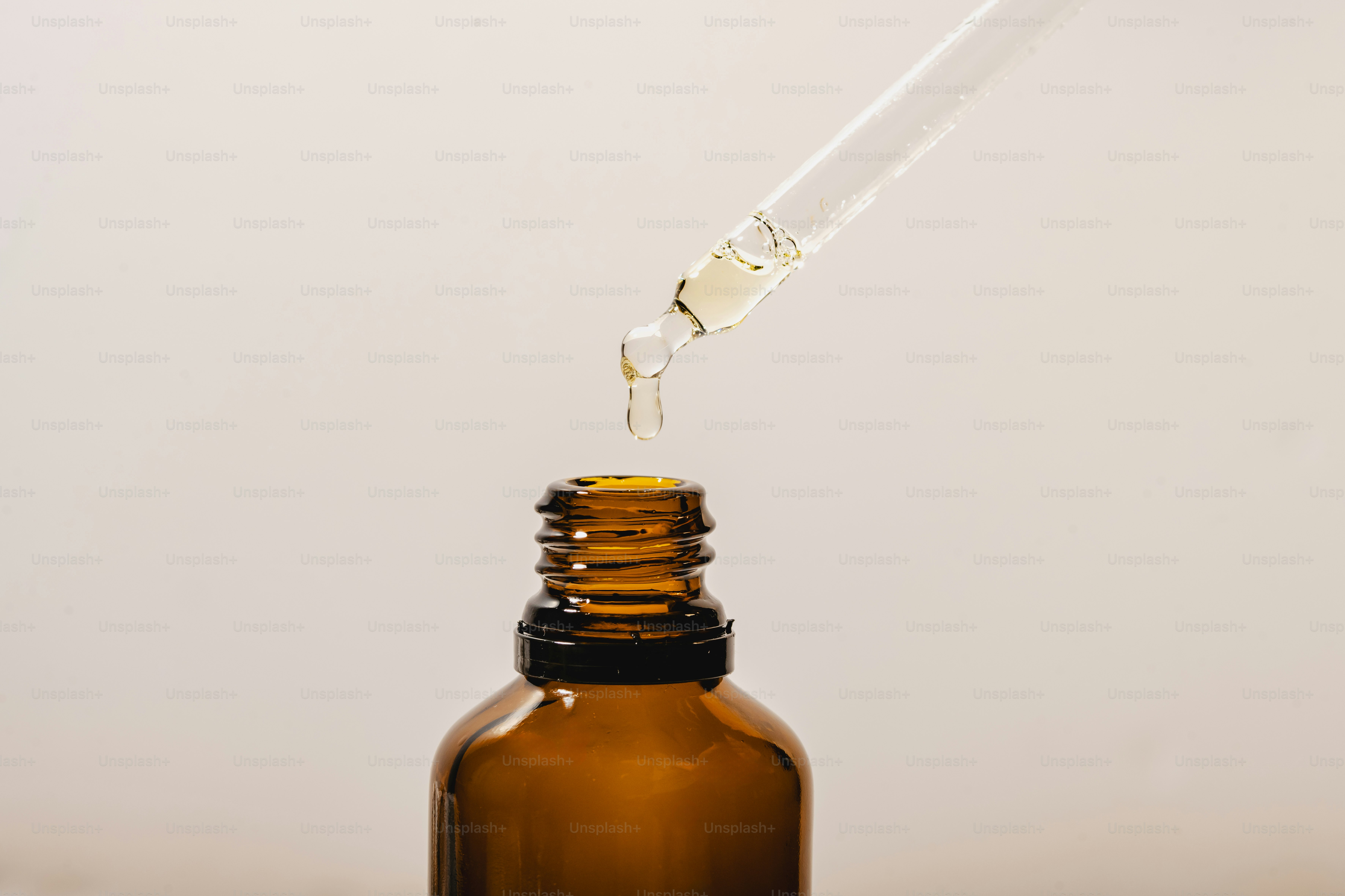 Dropper releasing liquid into amber bottle photo – Minimalist Image on ...