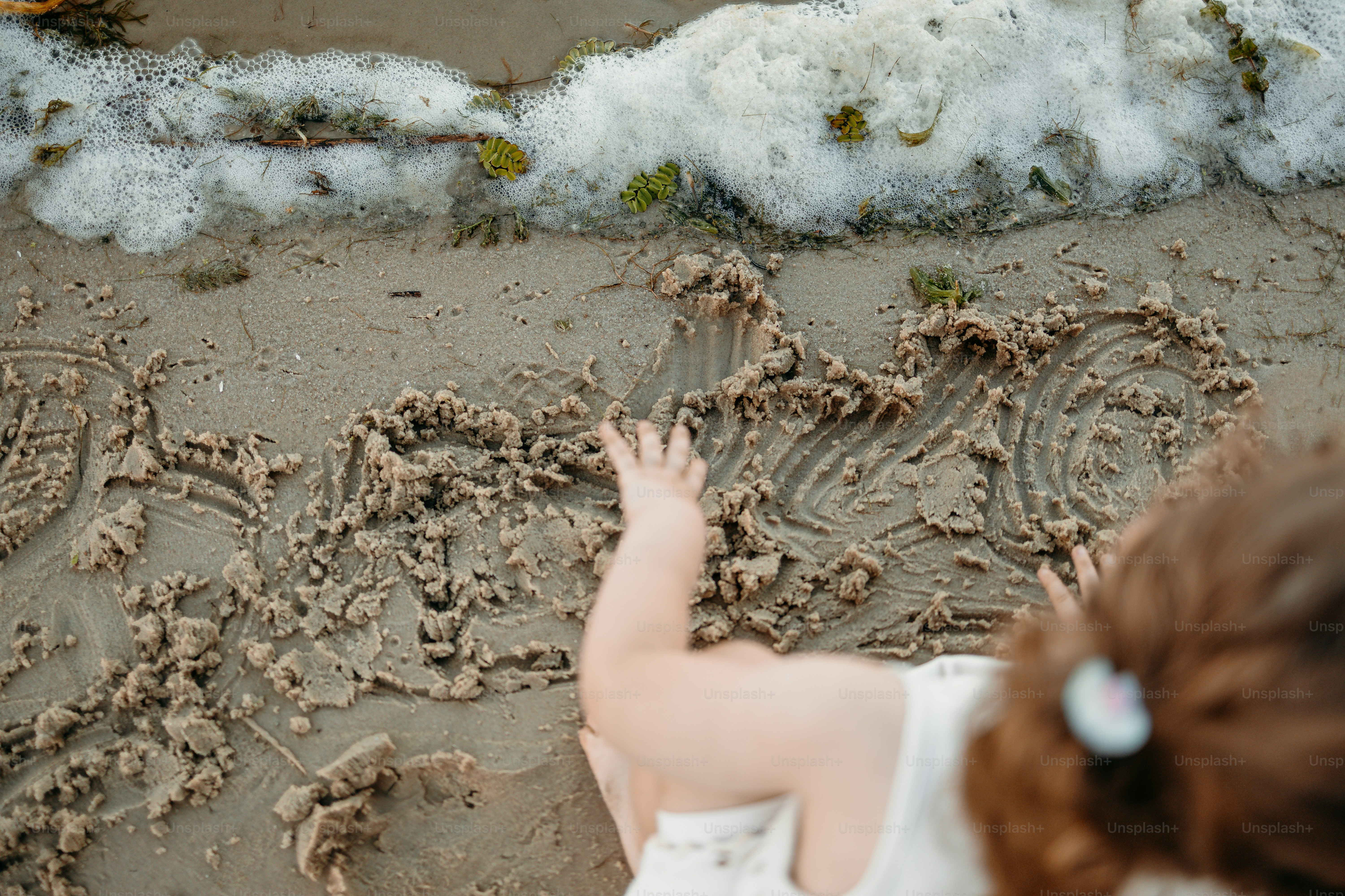 Child drawing in the sand near the ocean waves photo – Beach Image on ...