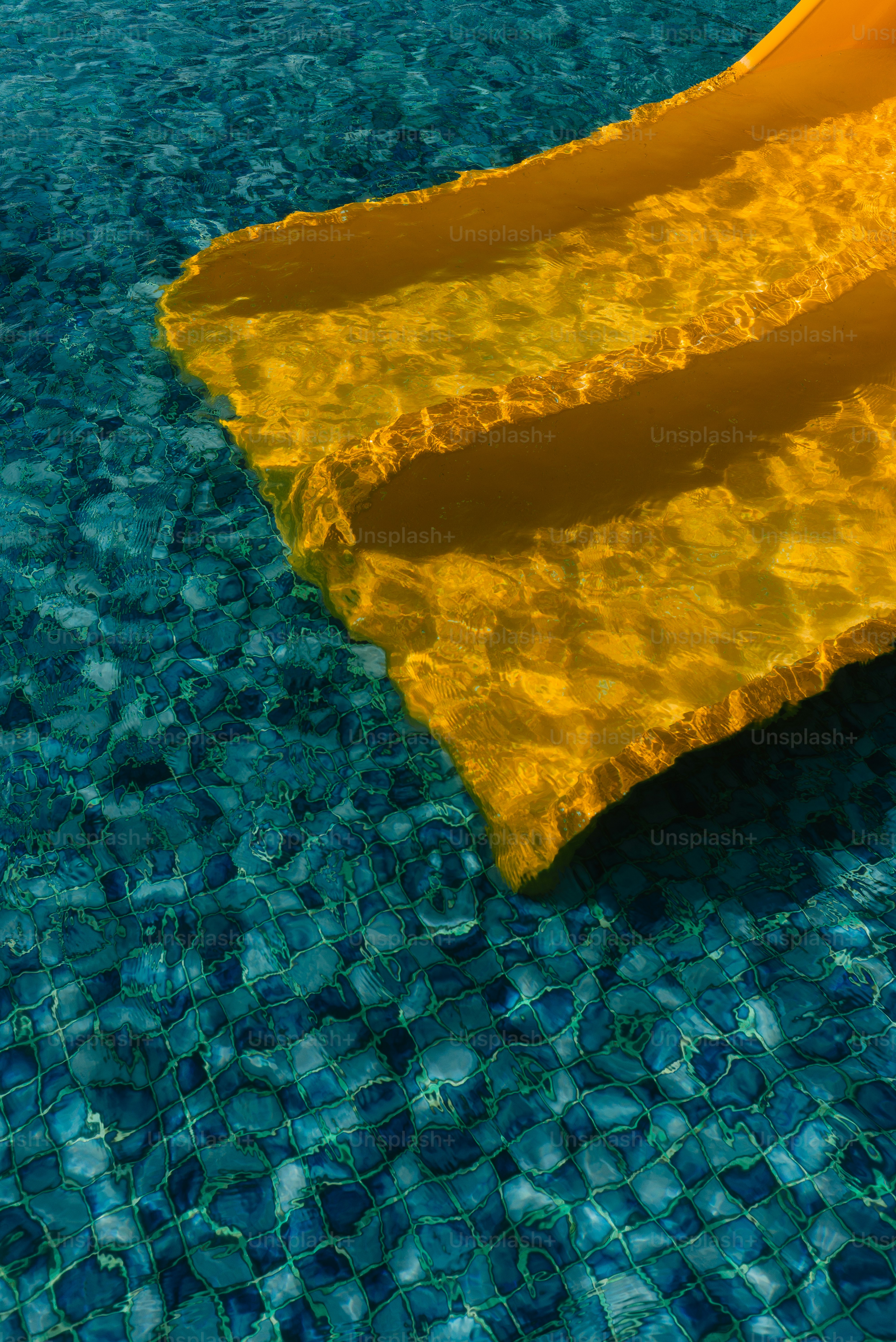 Yellow inflatable slide partially submerged in pool water. photo ...