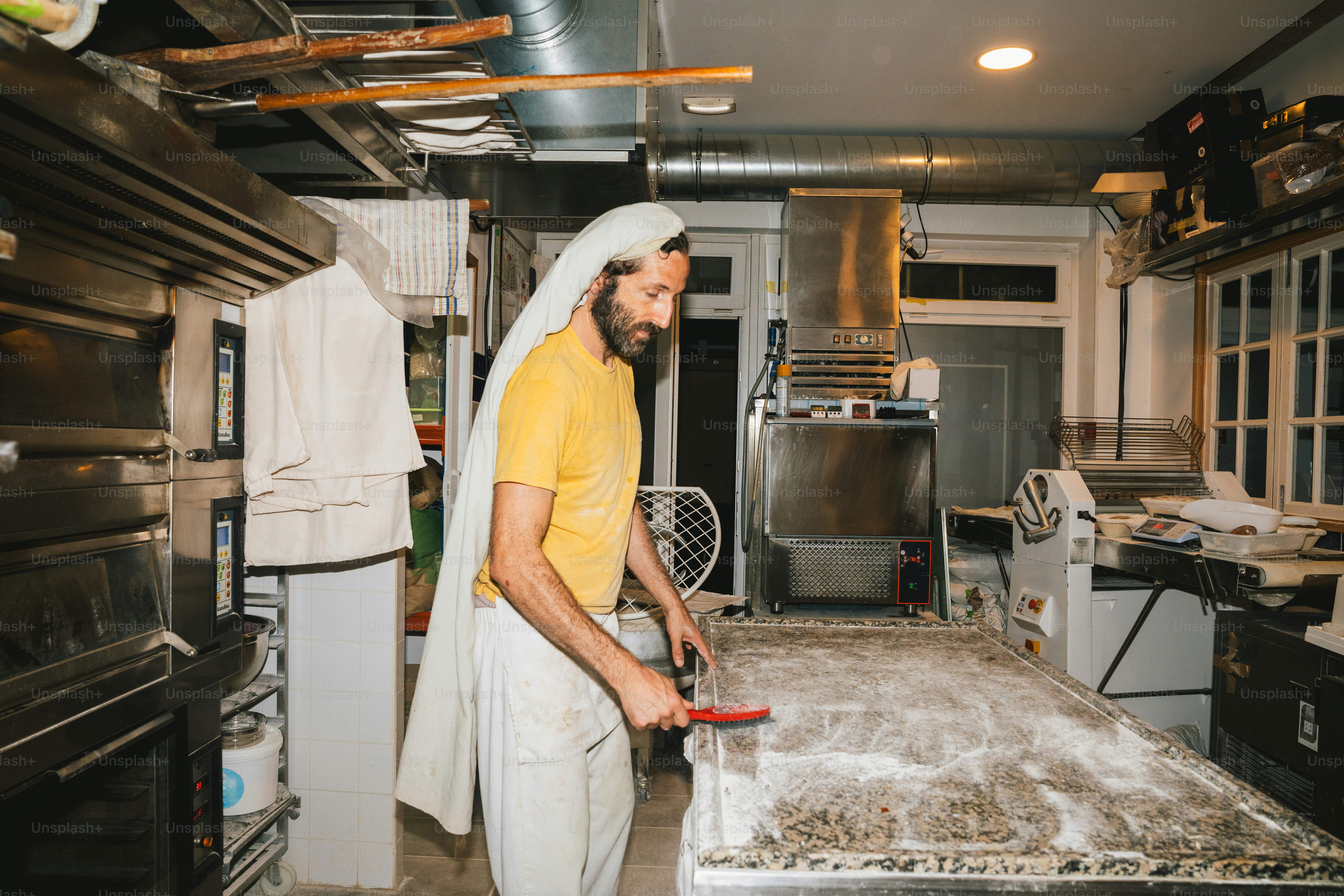 Baker dusting flour on a large work surface photo – Bakery Image on ...