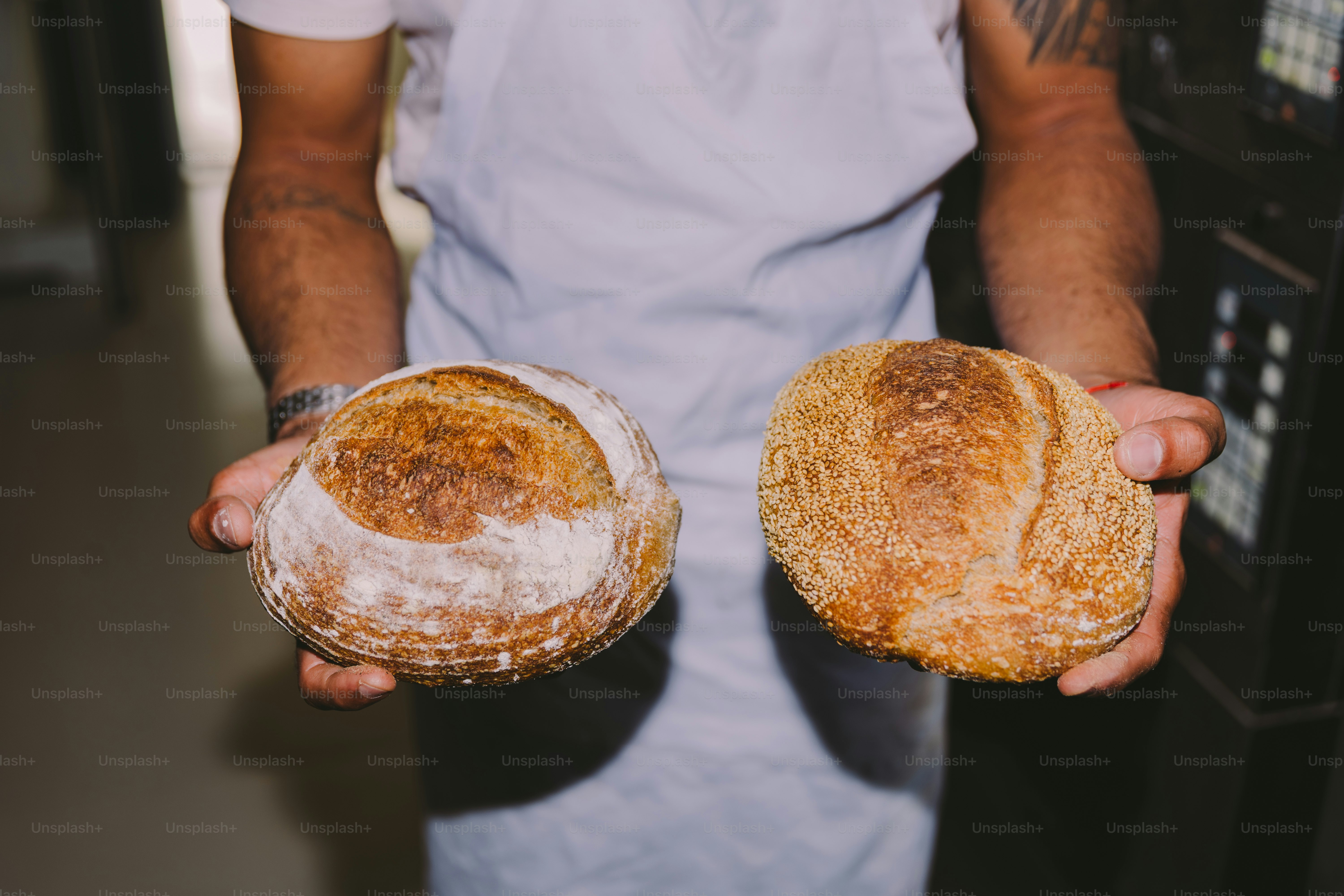 Baker holding two loaves of freshly baked sourdough bread. photo ...