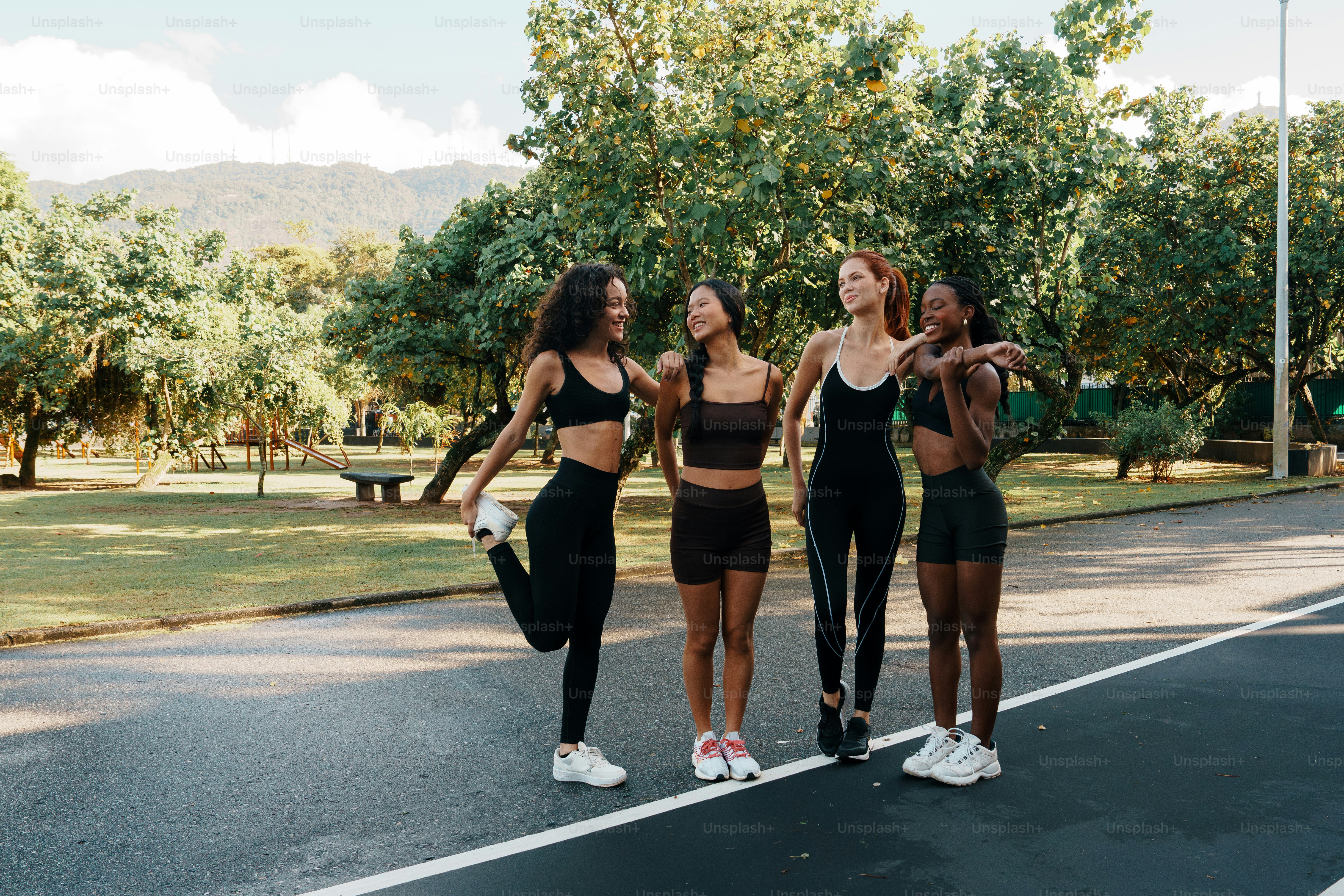 Four friends laughing while sitting on a bench outdoors. photo ...
