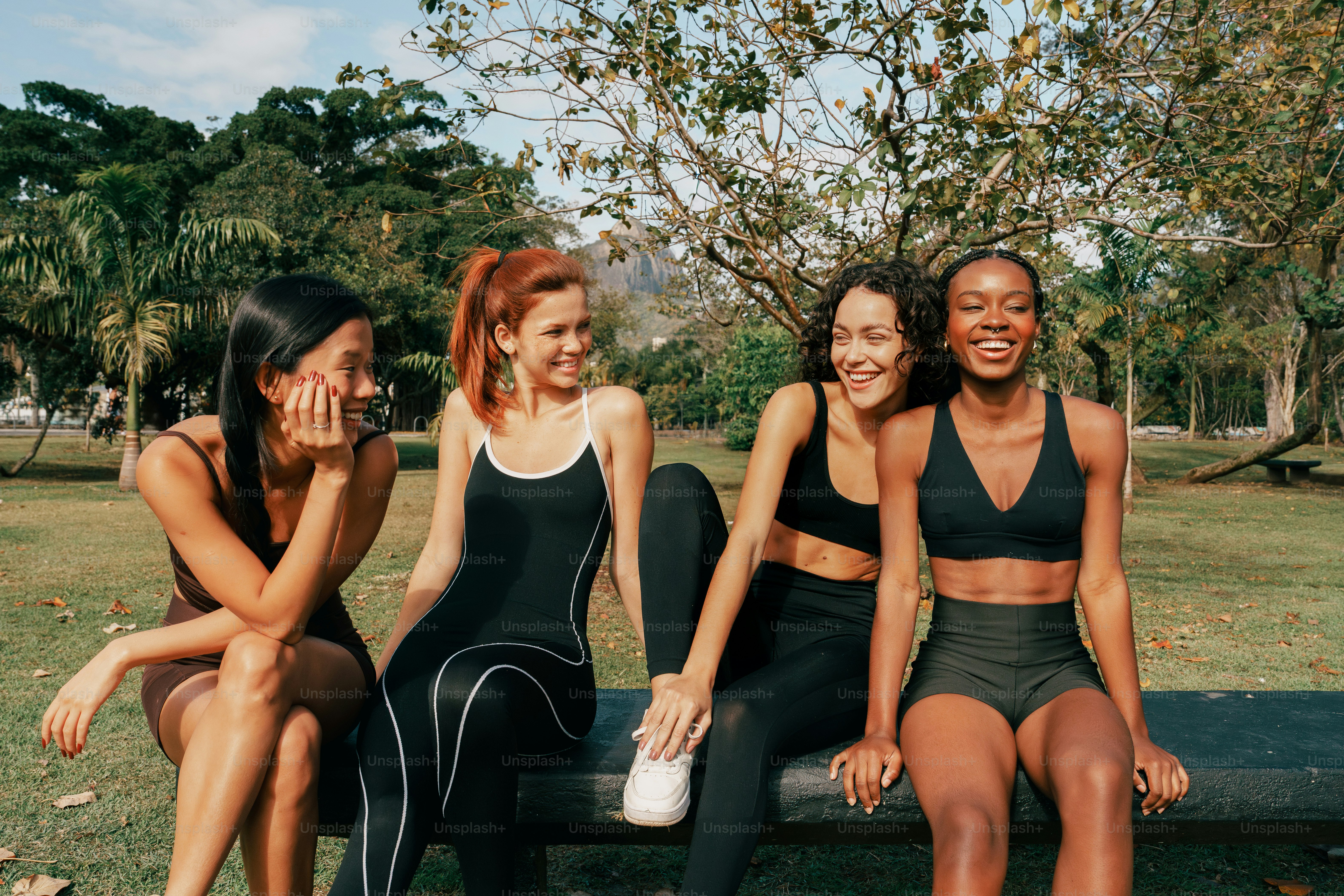 Four friends laughing while sitting on a bench outdoors. photo ...