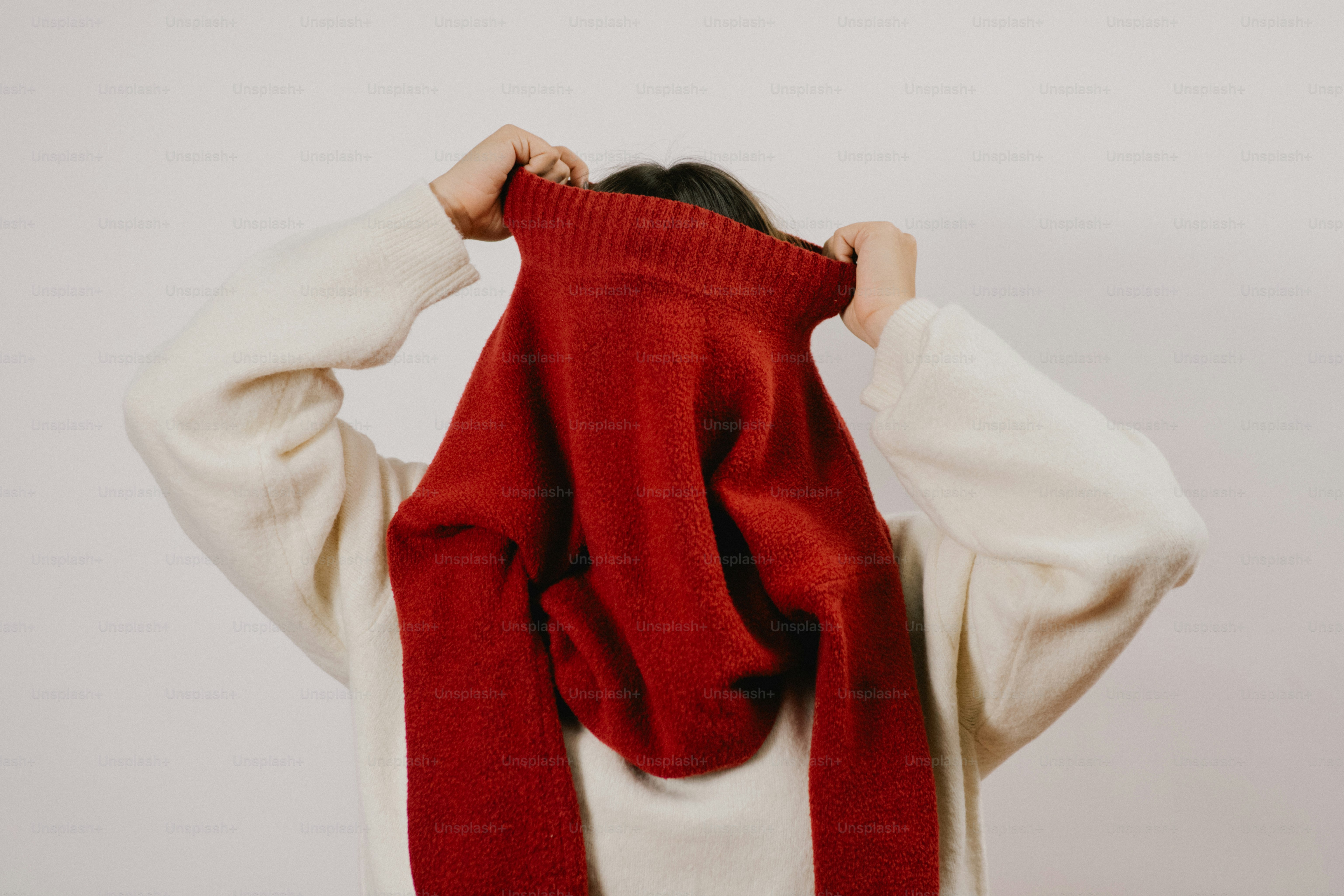 Person pulling red sweater over head photo – Winter fashion Image on ...