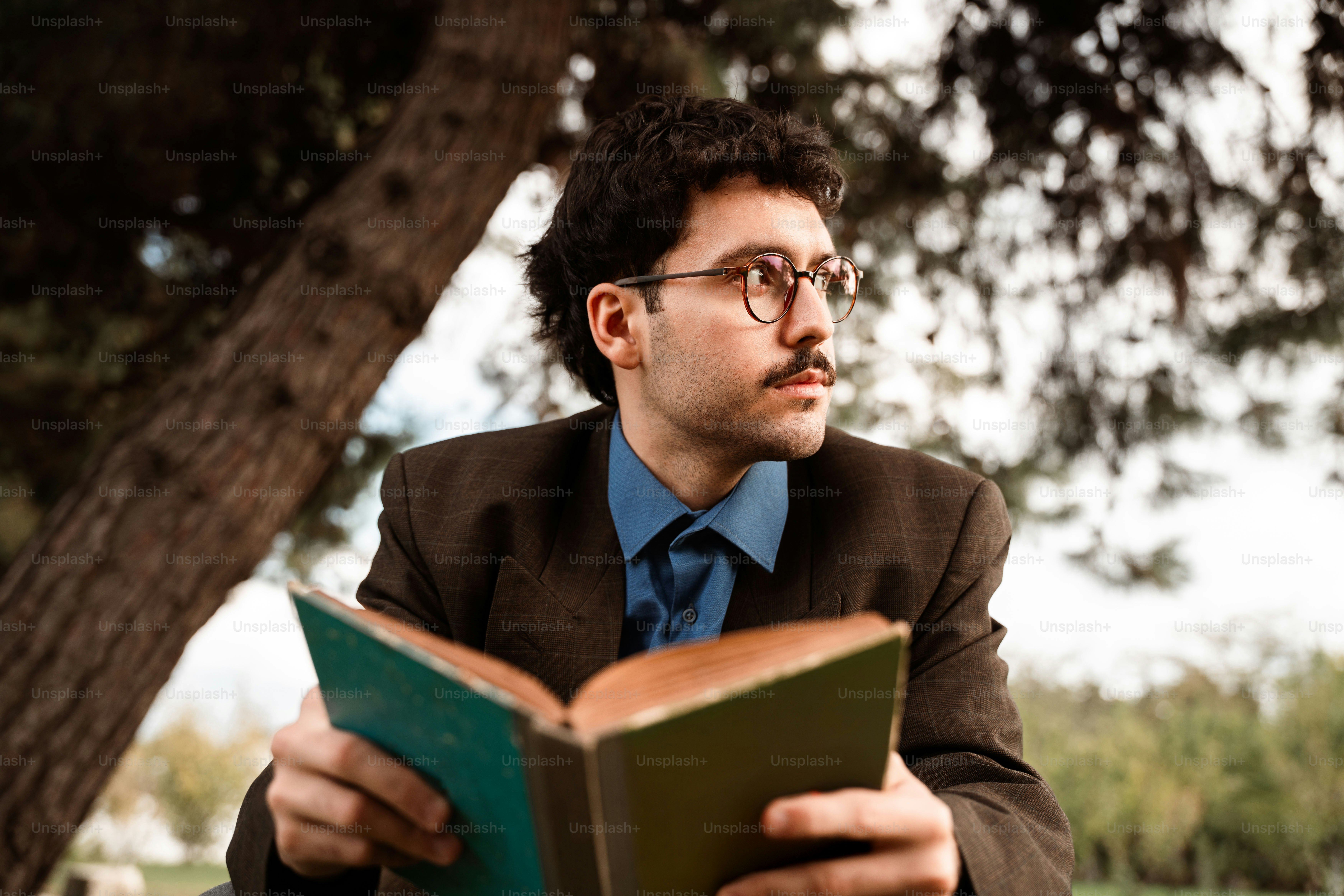 Man with glasses reading a book outdoors photo – Man Image on Unsplash