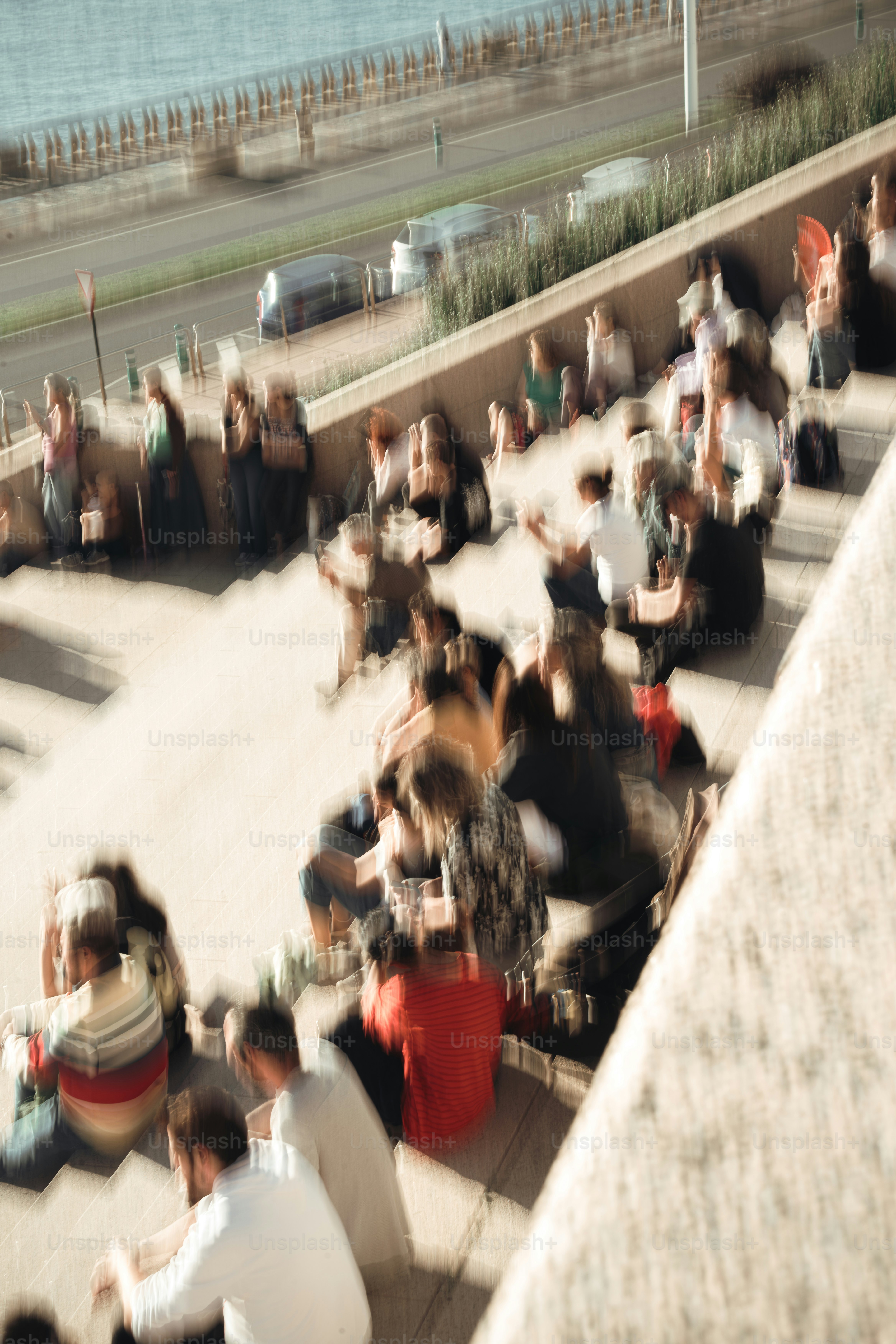 People sitting on outdoor stairs near a body of water. photo – People ...