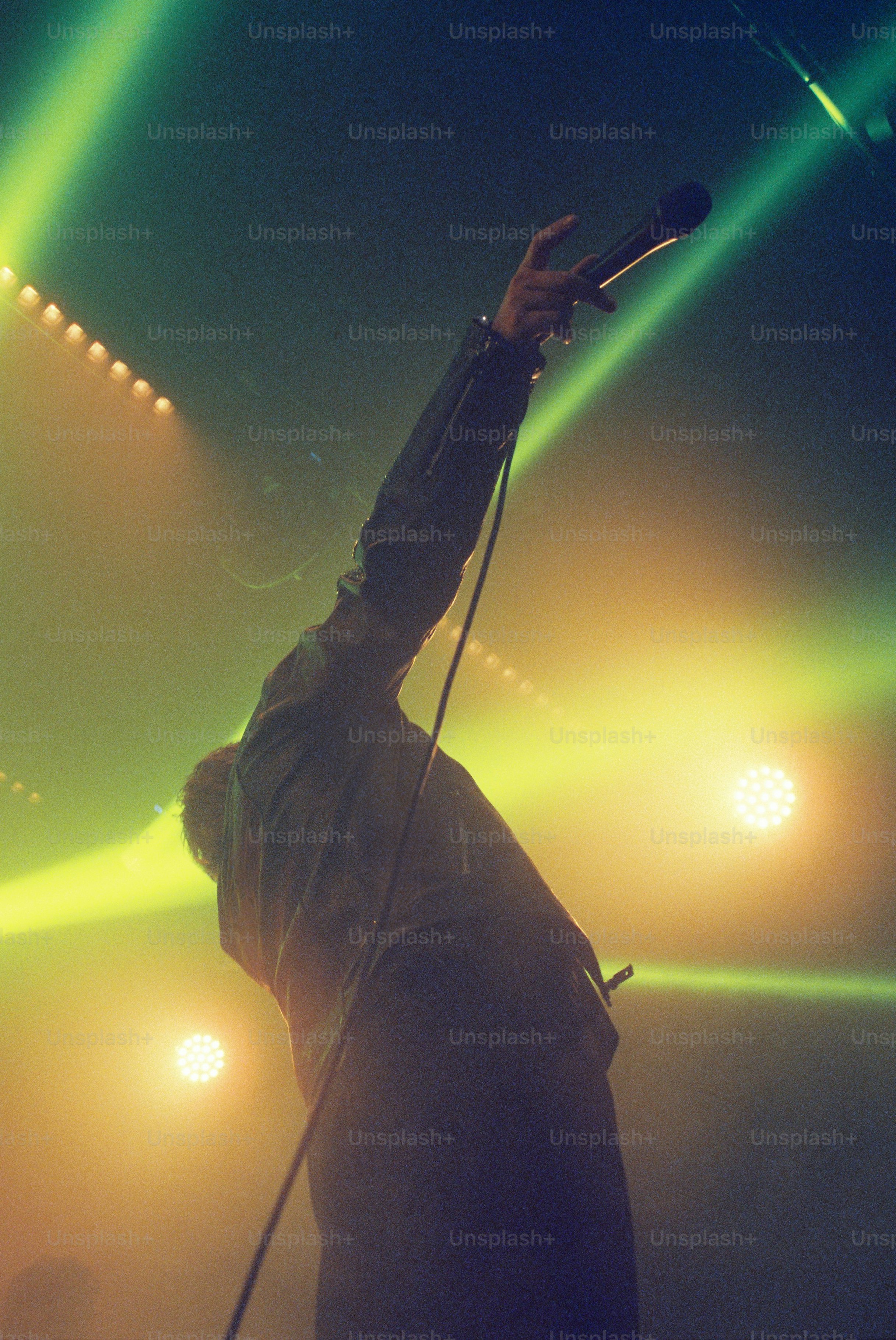 Singer holding microphone on stage with bright lights photo – Film ...