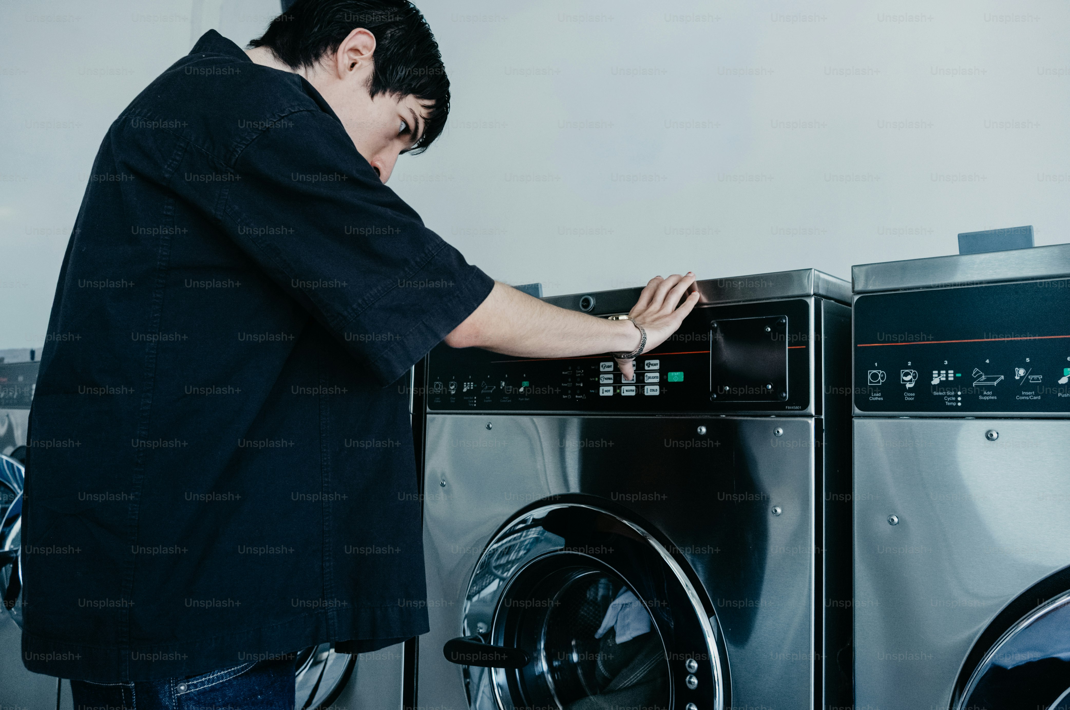 Man loading clothes into a washing machine. photo – Cleaning Image on ...