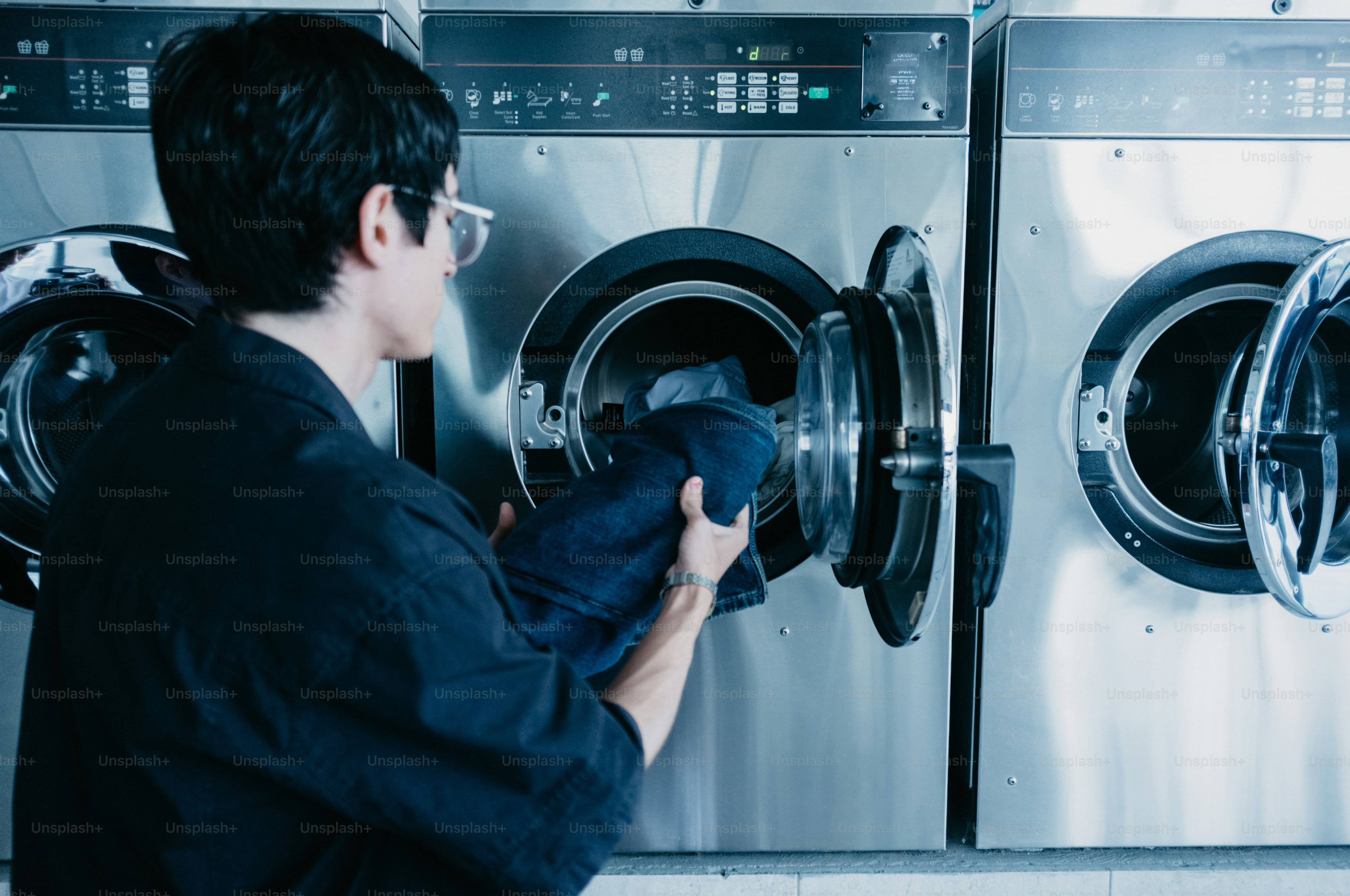 Man loading clothes into a washing machine. photo – Cleaning Image on ...