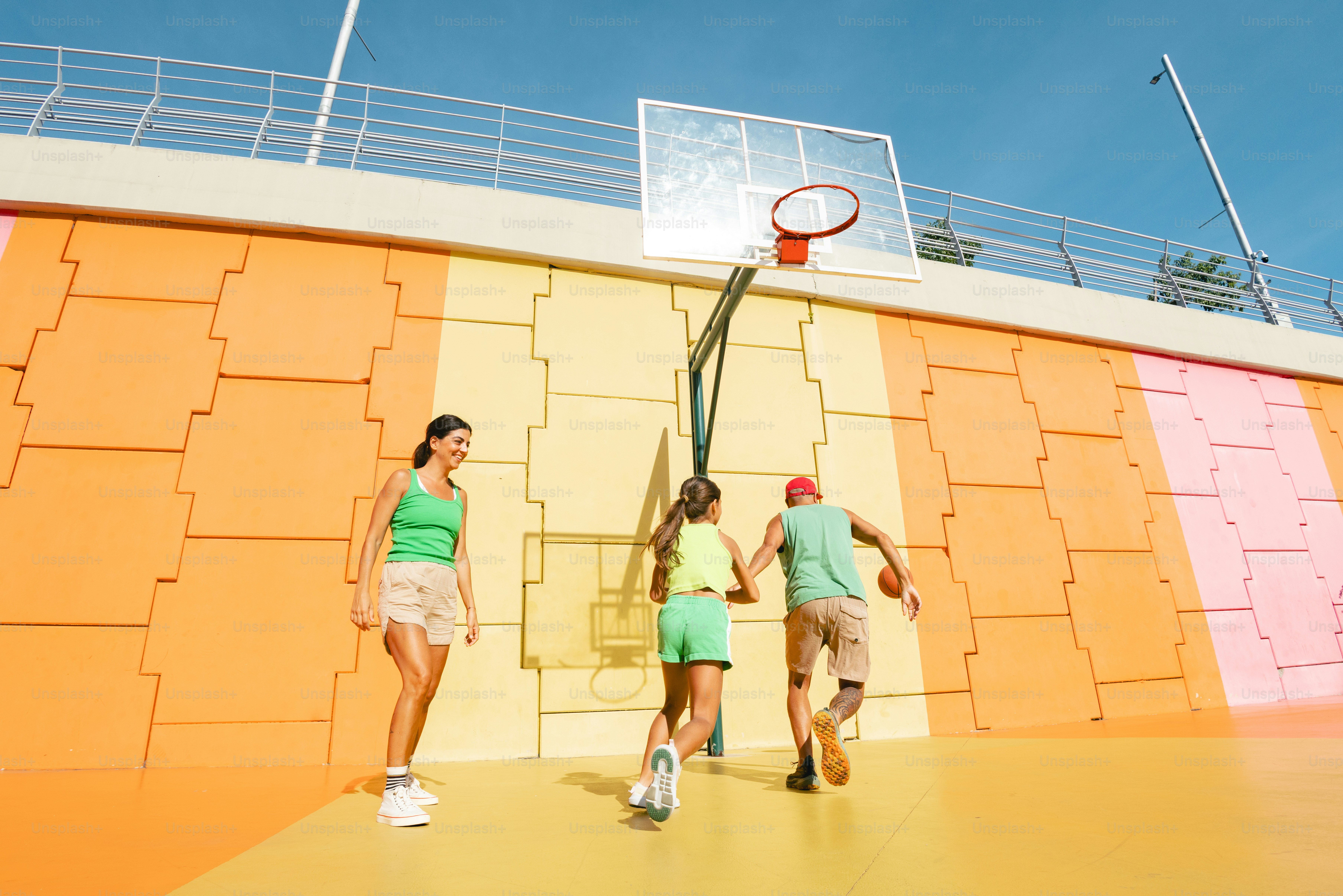 Three friends playing basketball on a colorful court. photo – Family ...