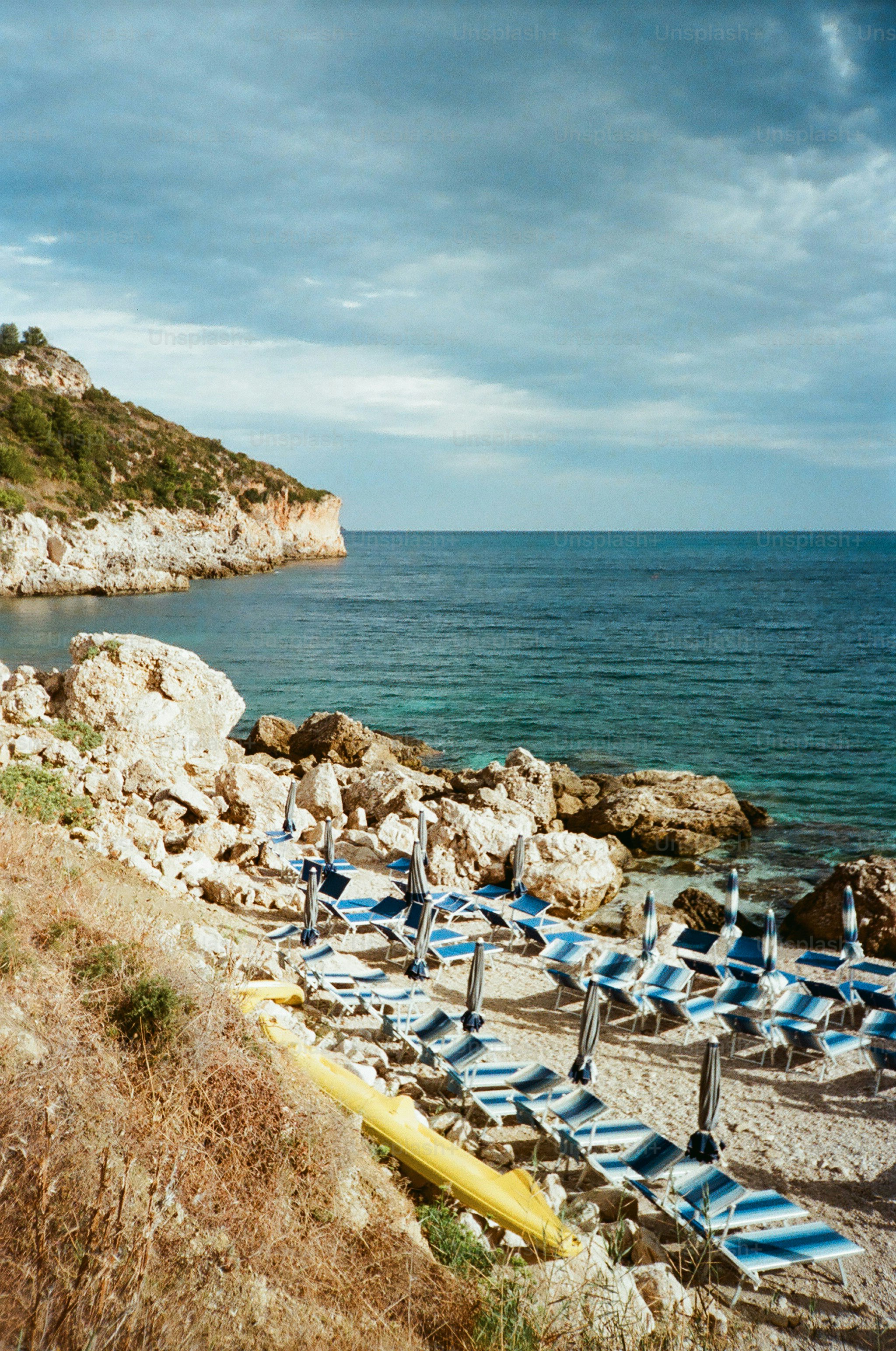 Beach chairs and umbrellas on a rocky shore. photo – Beach Image on ...