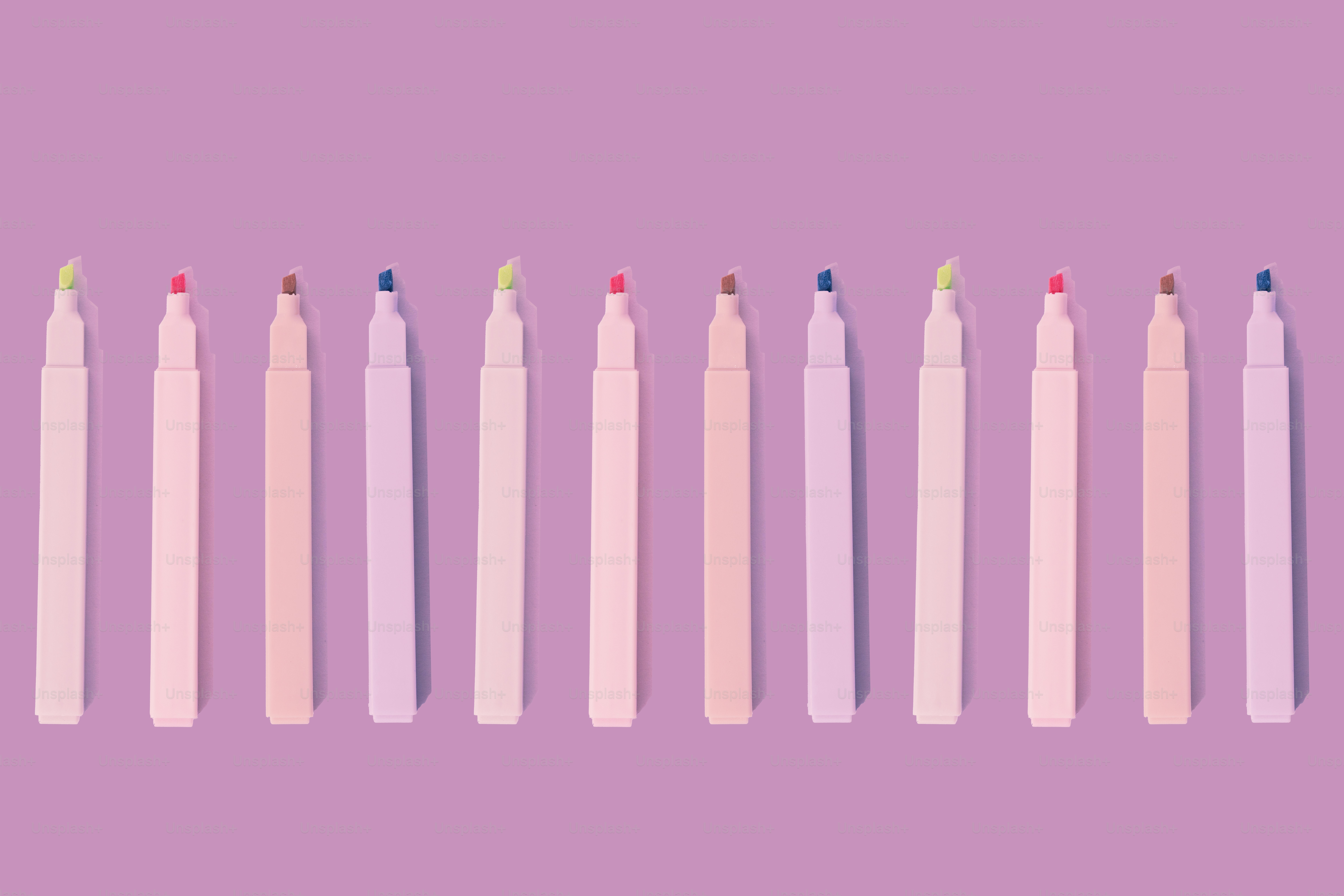 A row of pastel colored markers on purple background photo – Purple ...