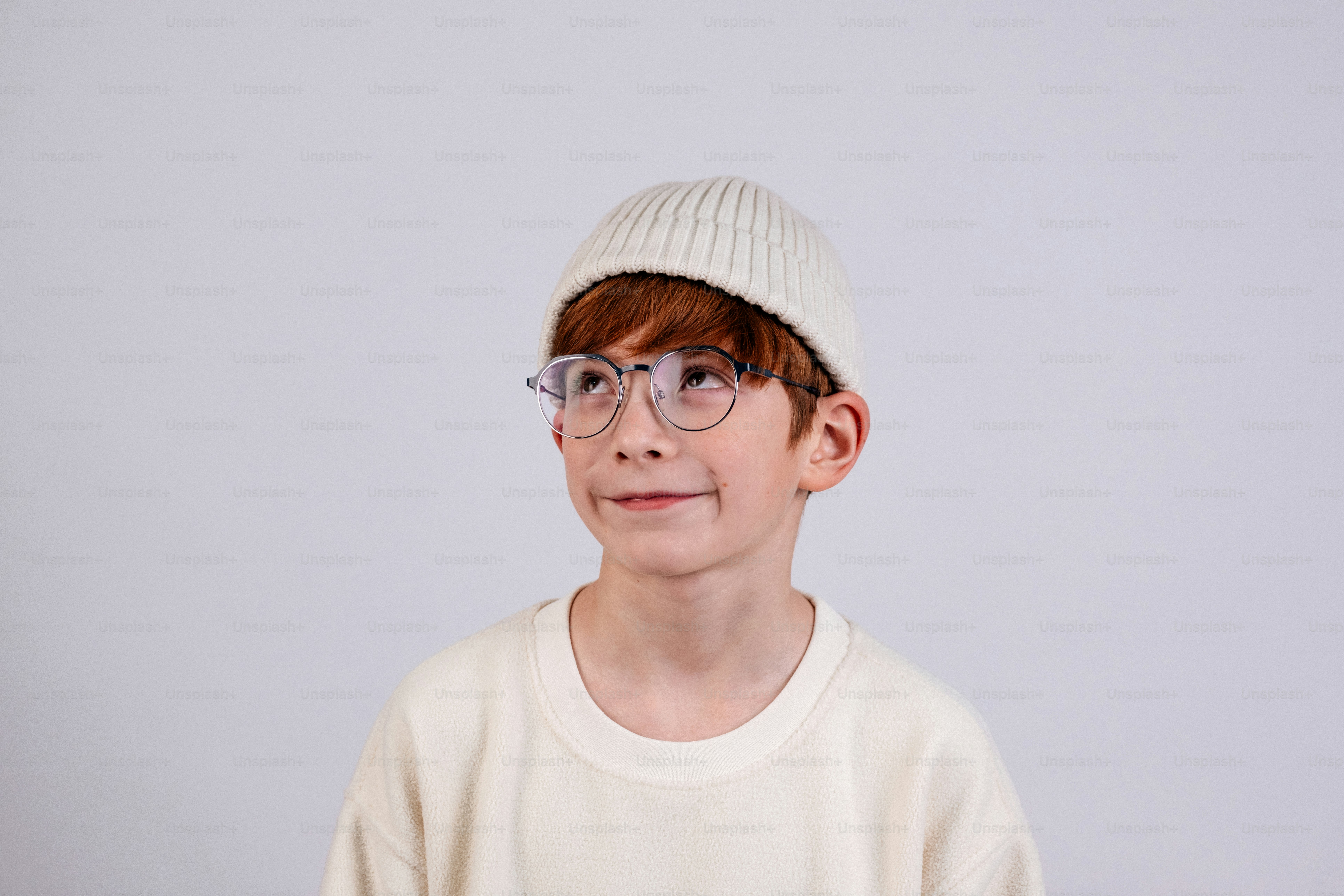 Jeune garçon aux cheveux roux portant un bonnet et des lunettes. photo ...