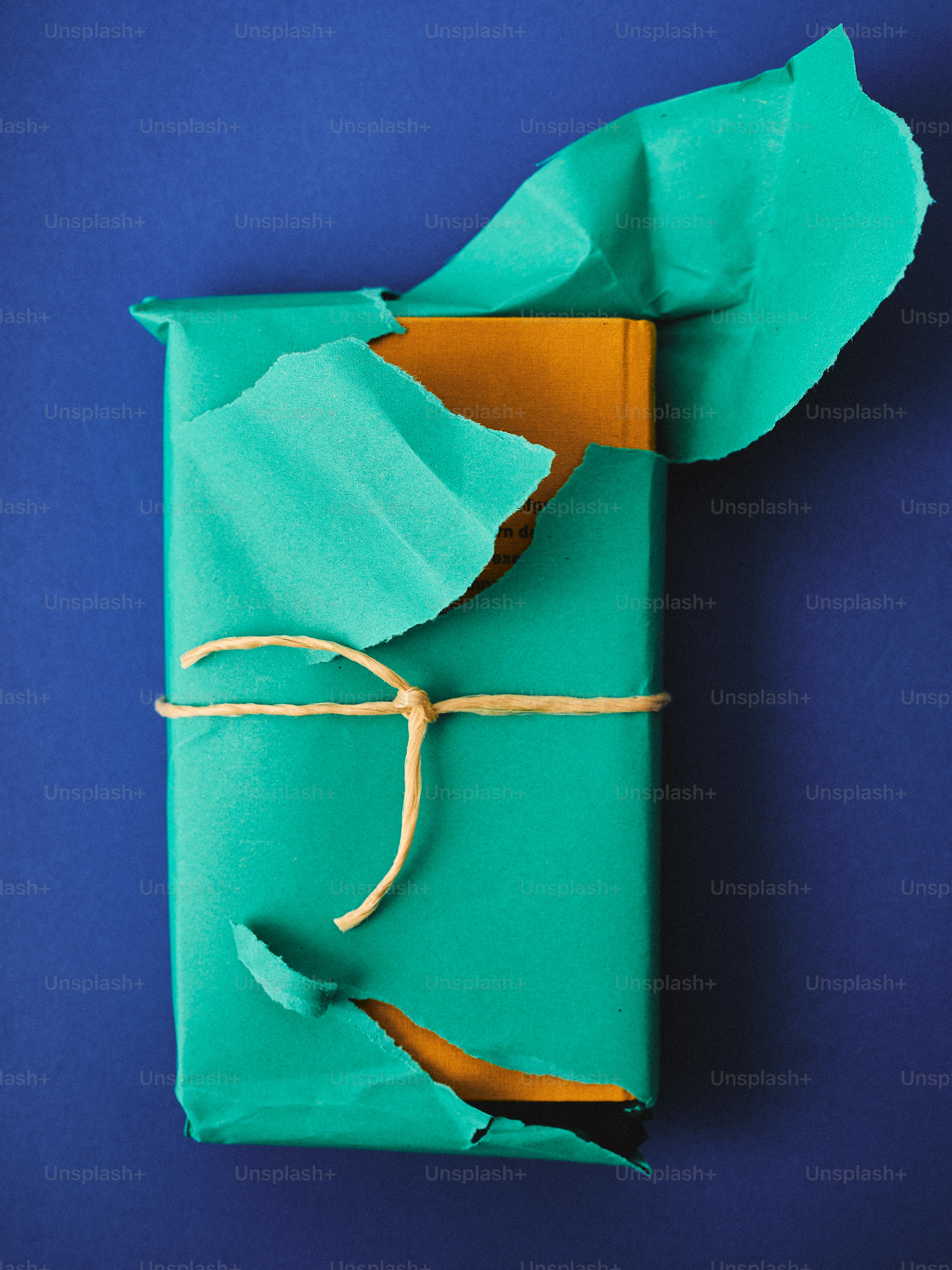 A gift wrapped in red paper with white string. photo – Book Image on ...