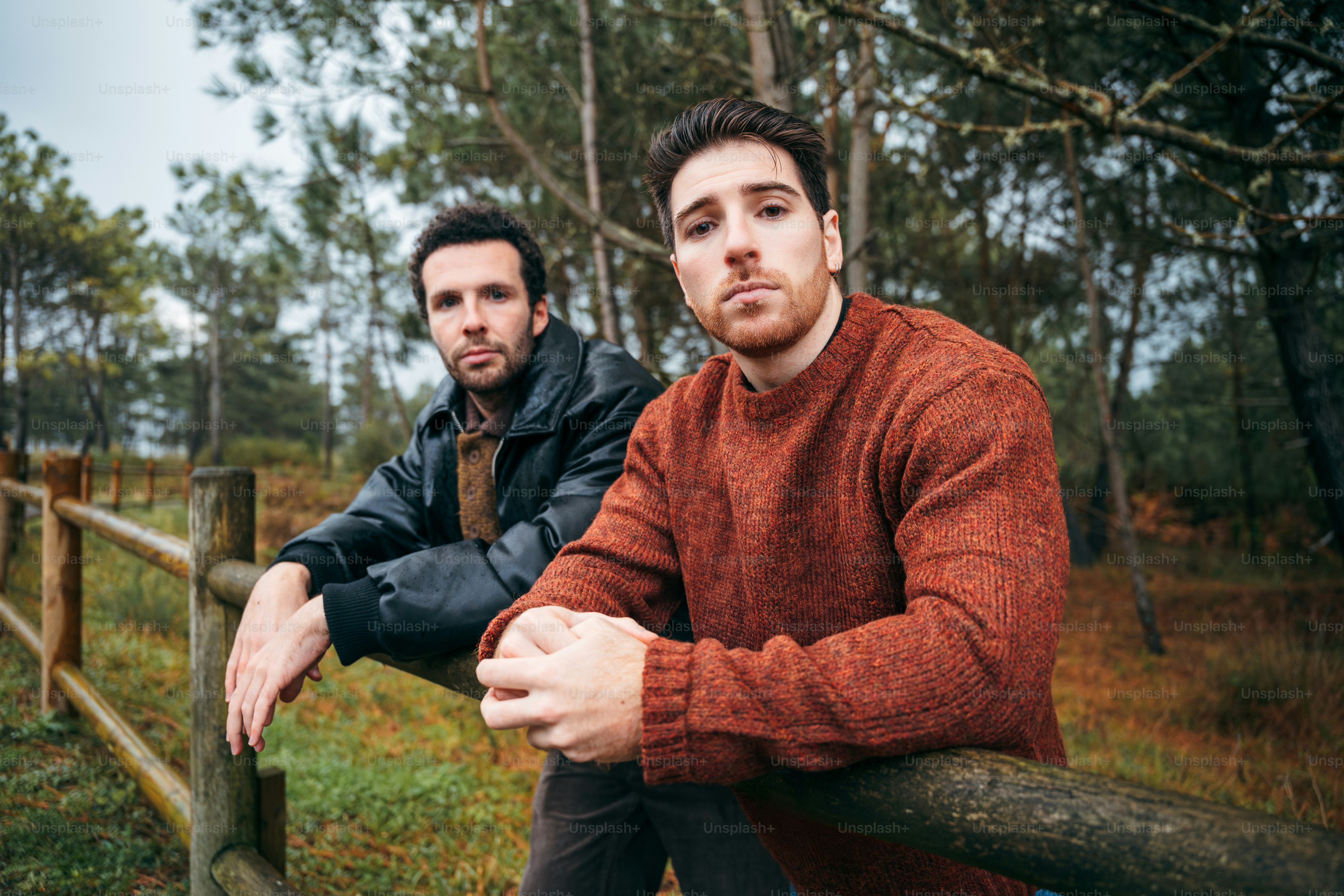 Two men posing by a wooden fence in a forest. photo – Fashion Image on ...
