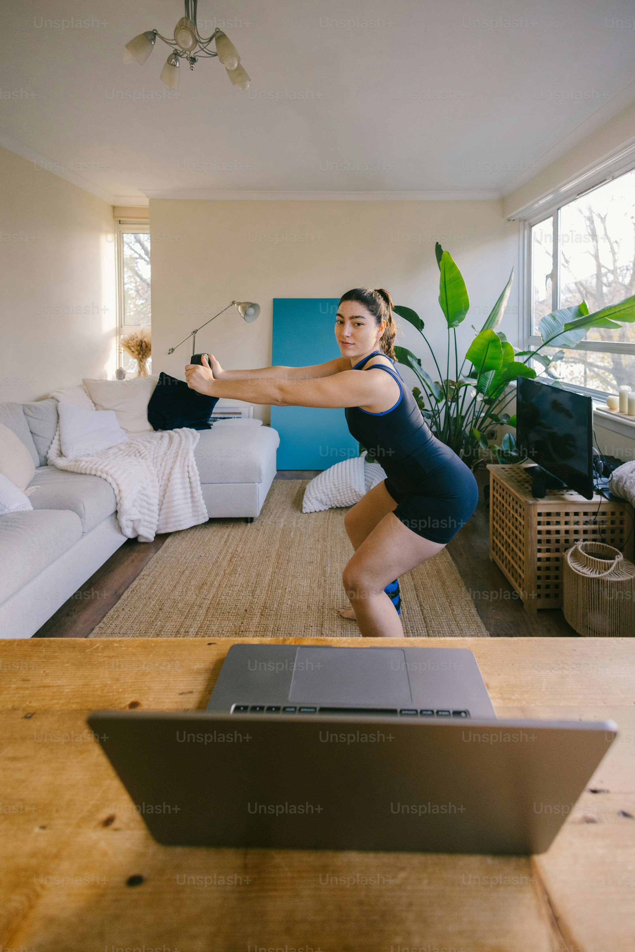 Woman exercising in living room following online workout photo ...