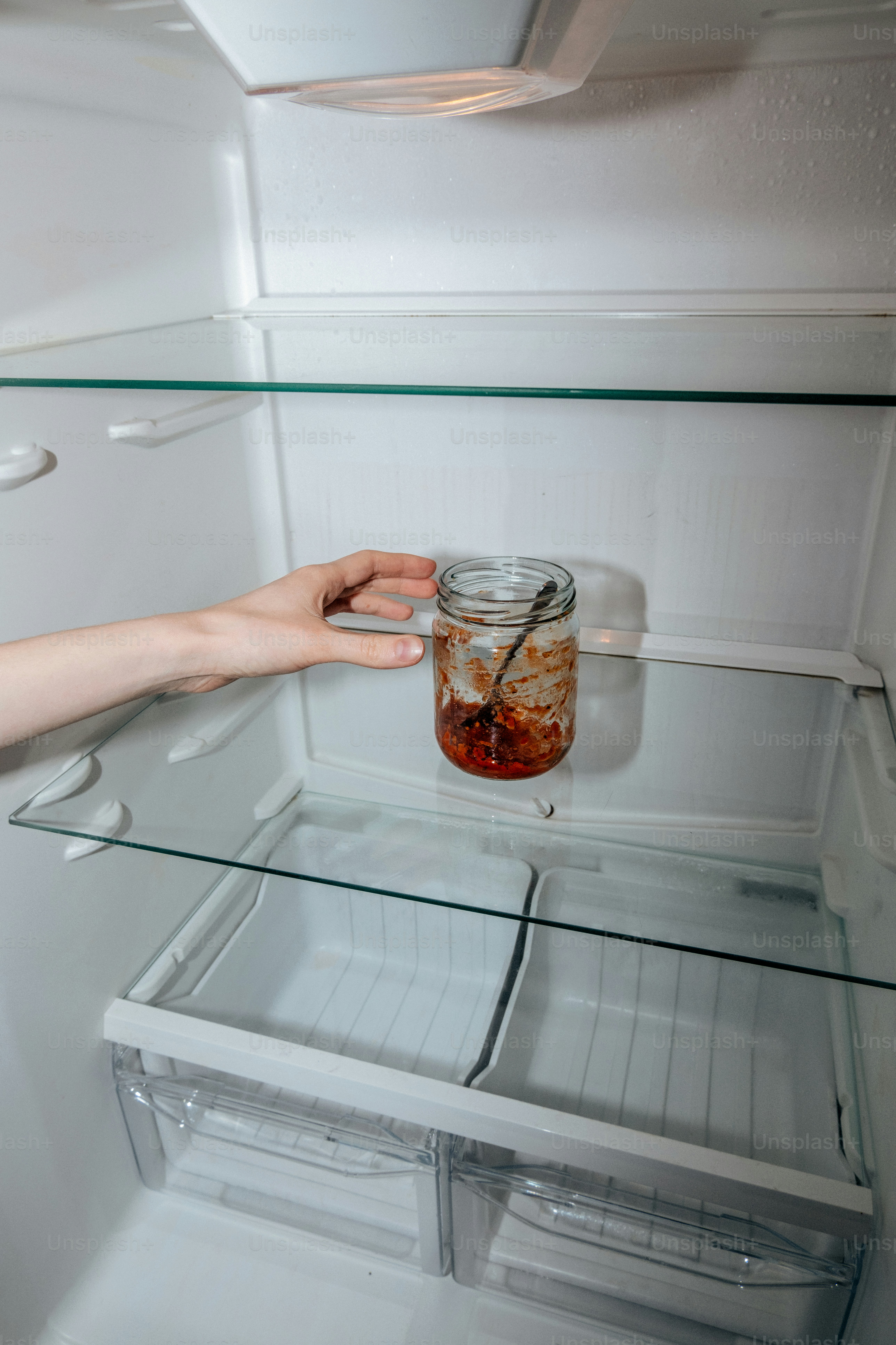 Hand reaching for a nearly empty jar in refrigerator photo – Crisis ...