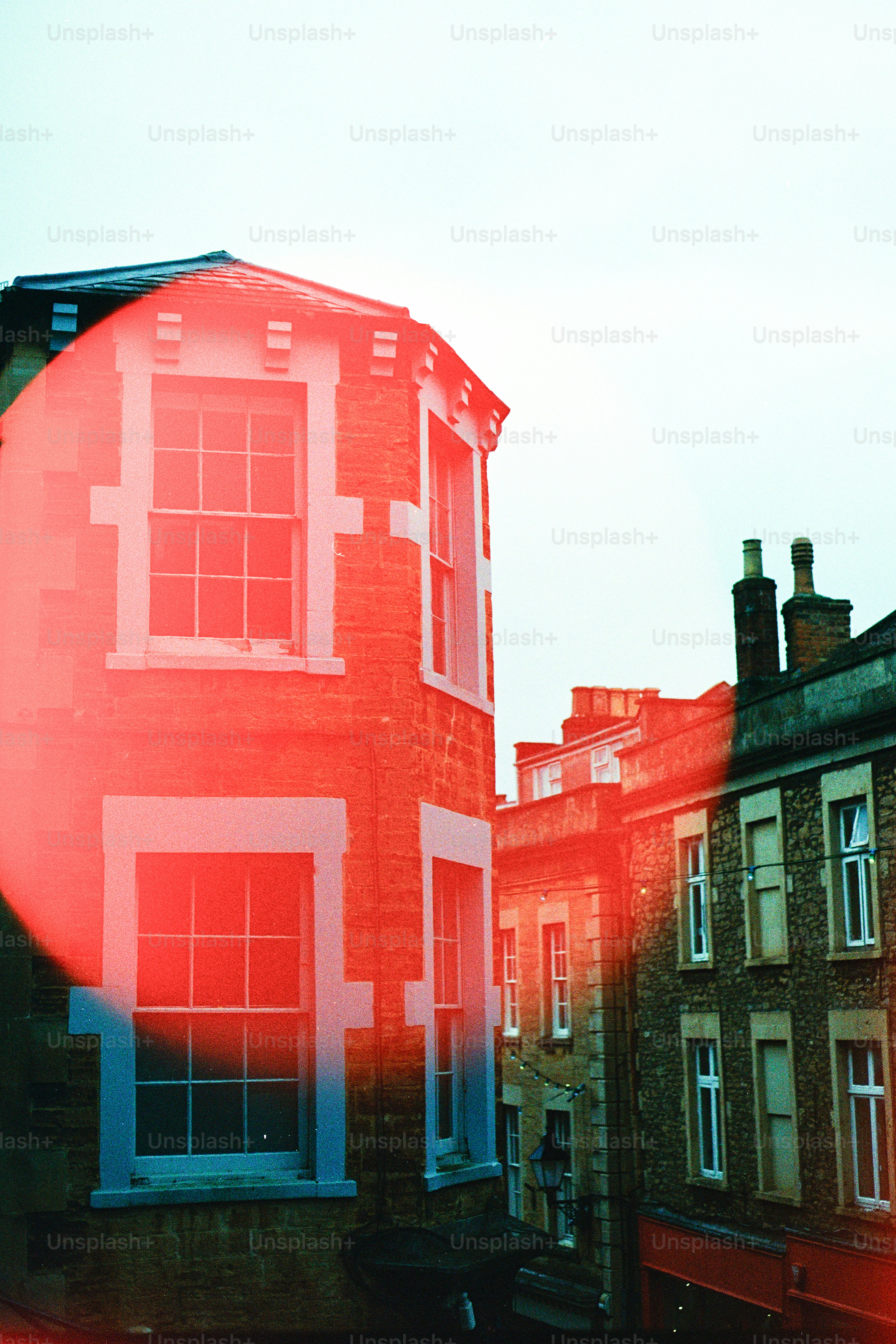 Brick buildings with white-trimmed windows and red lens flare. photo ...