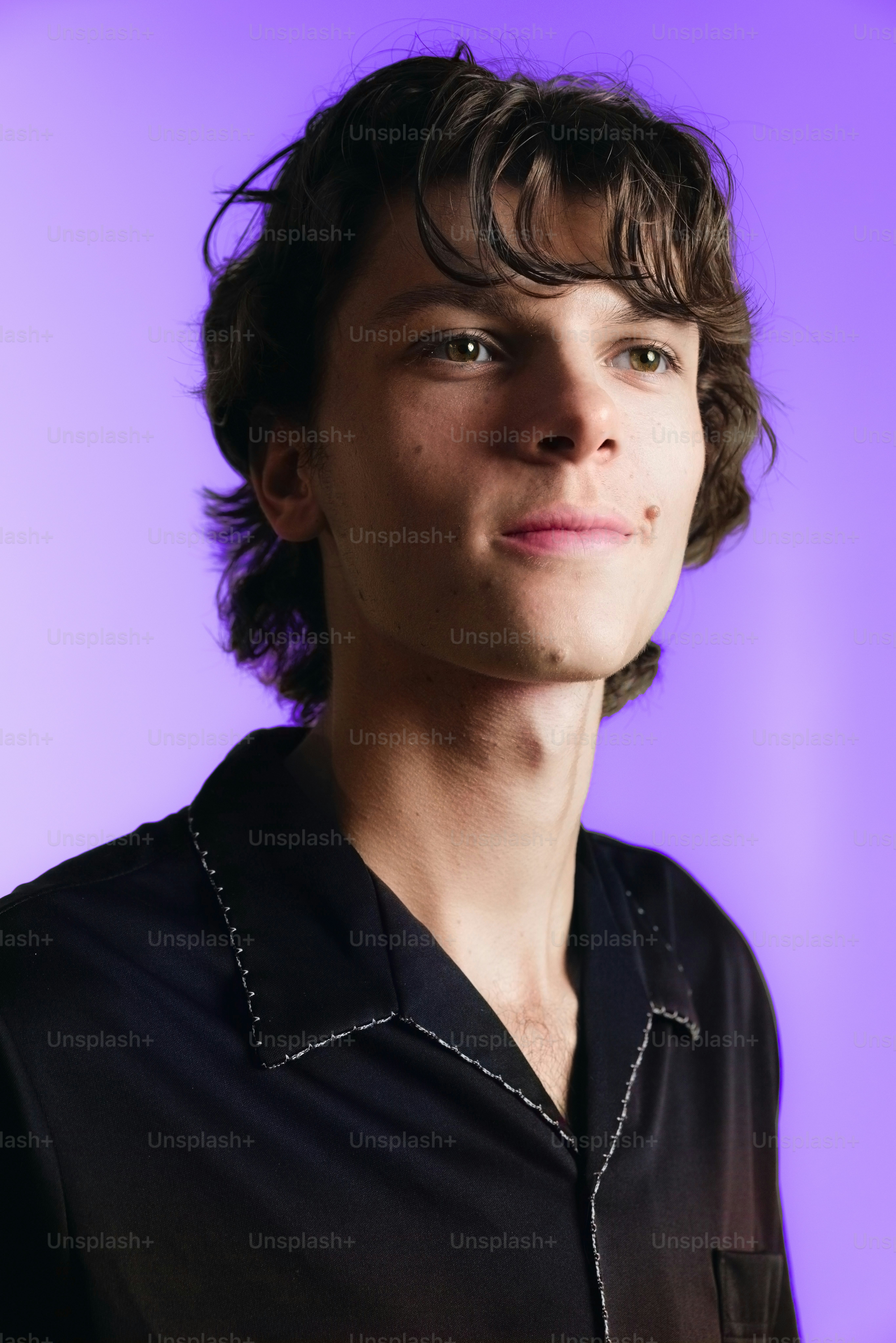 A young man with curly hair smiles softly. photo – Portrait Image on ...