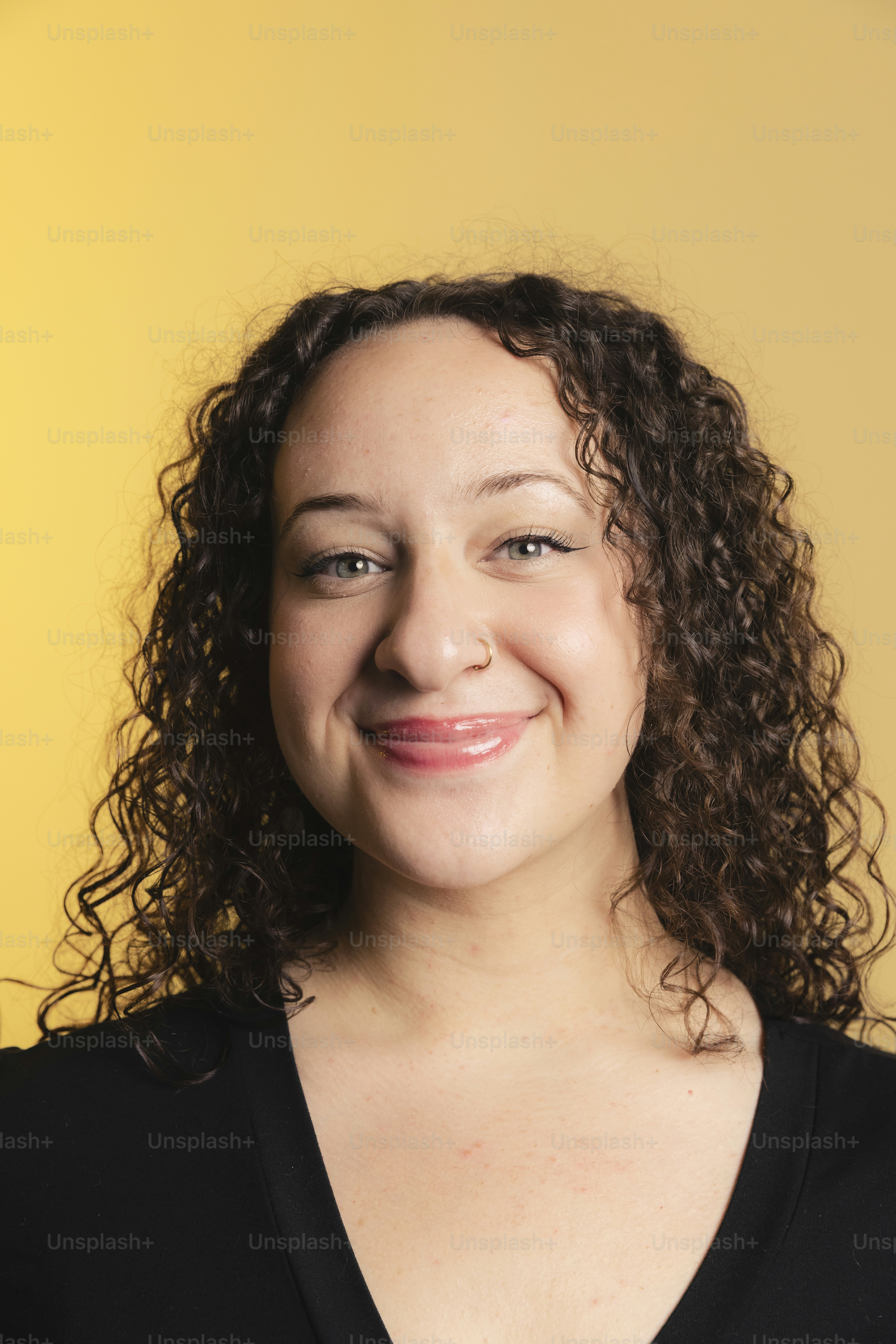 A smiling woman with curly hair on yellow background photo – Portrait ...