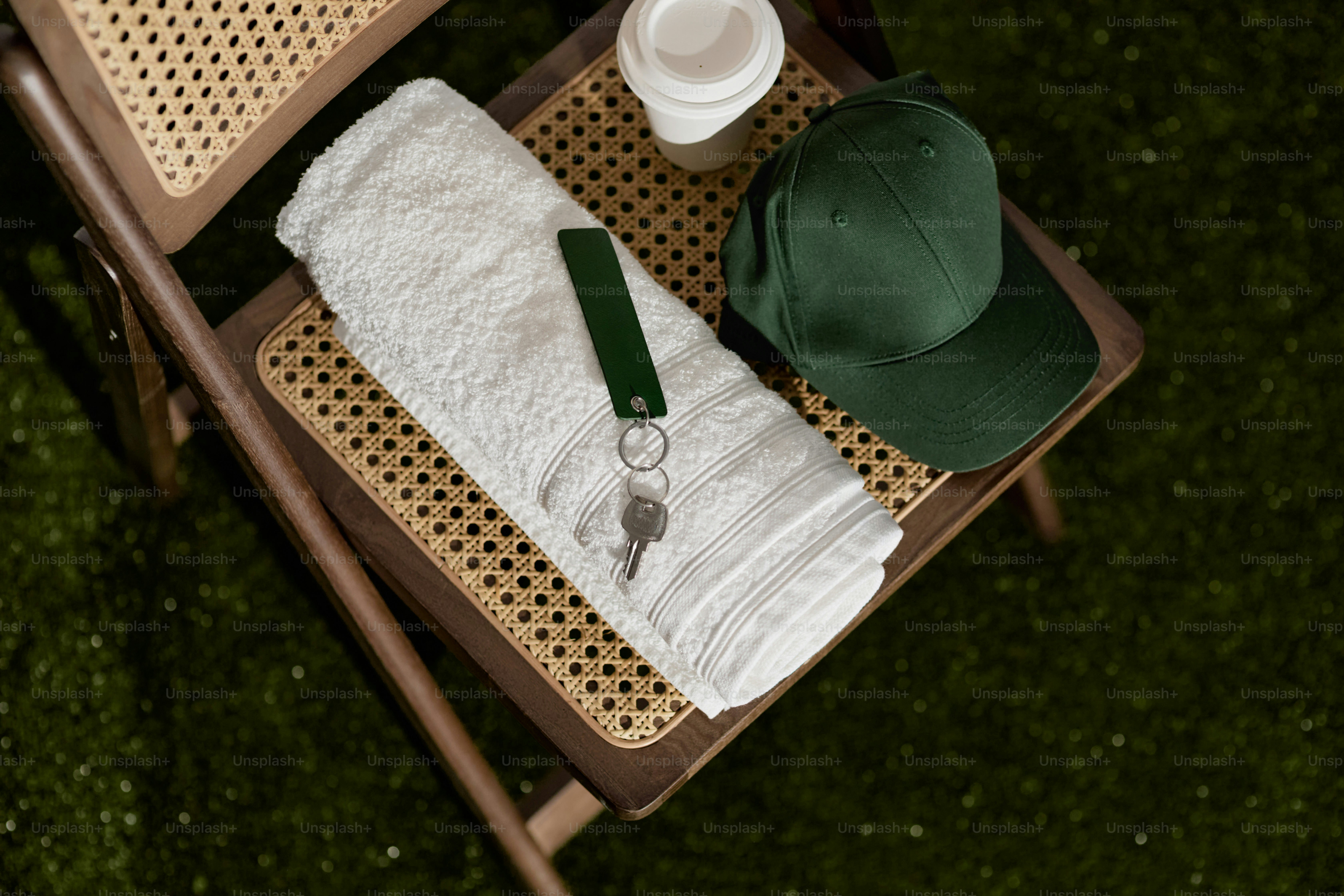 White towel, keys, and green cap on chair photo – Coffee cup Image on ...
