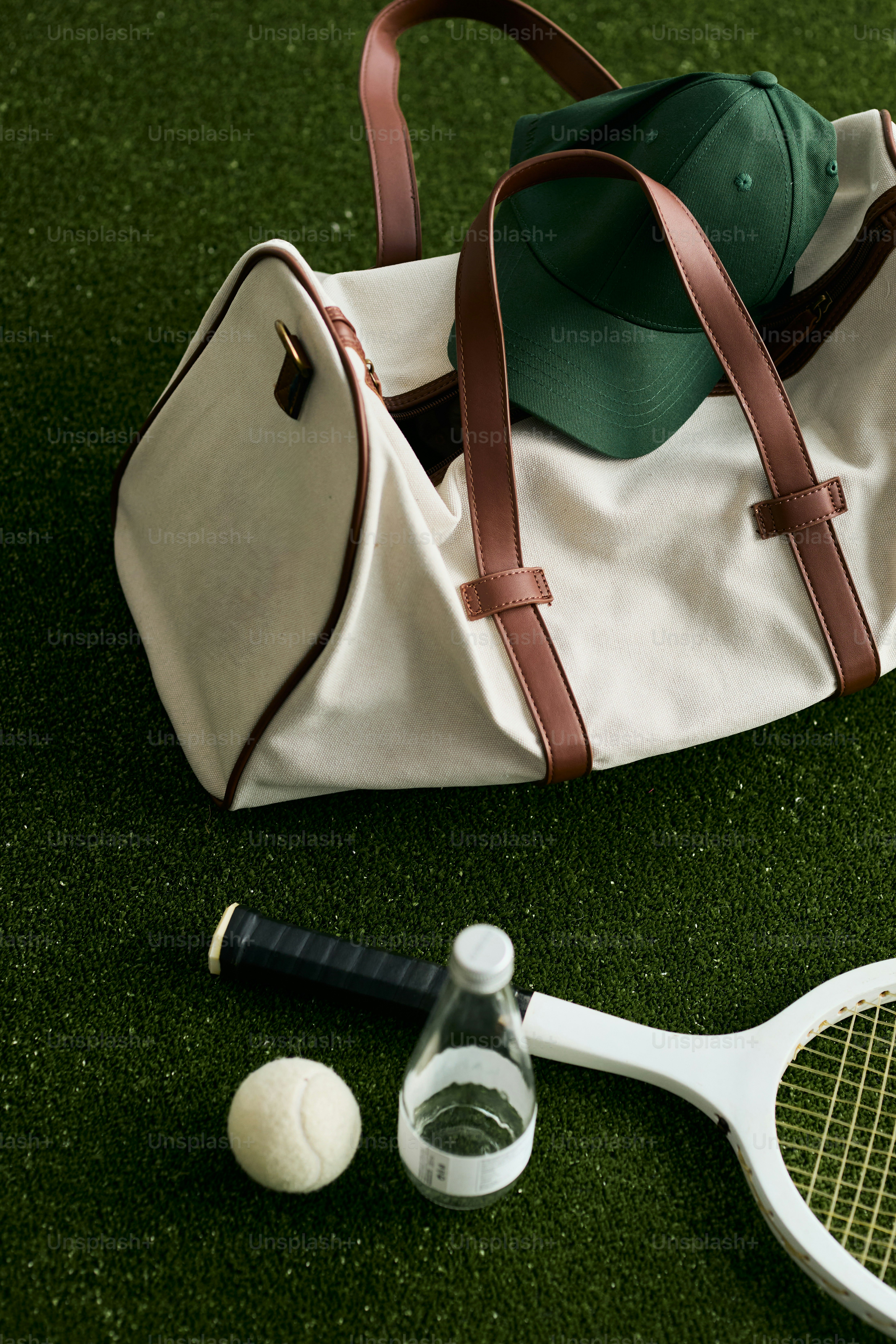 Tennis racket, ball, water bottle, and duffel bag on grass photo ...