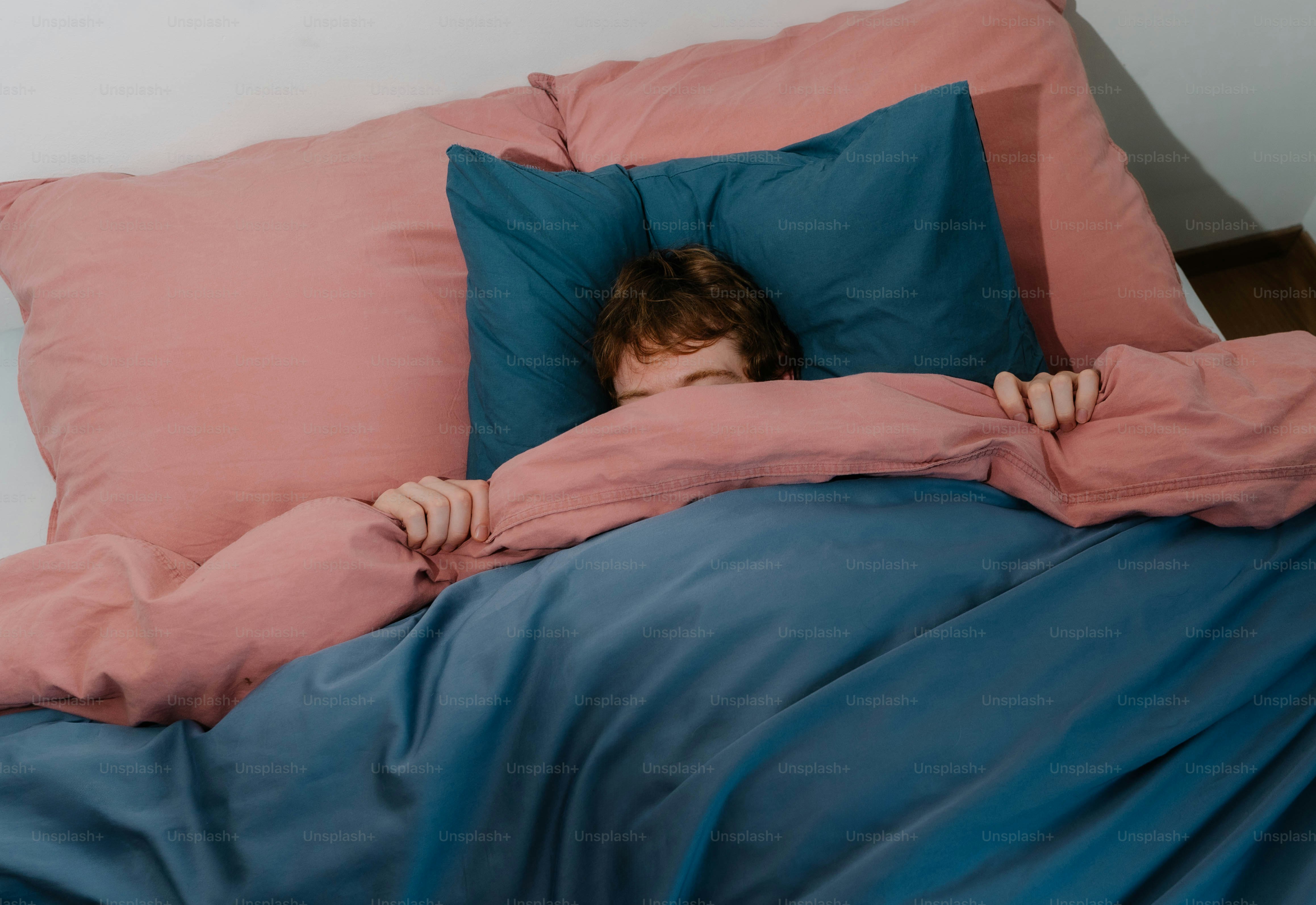 Child hiding under pink and blue blankets in bed. photo – Blue Image on ...
