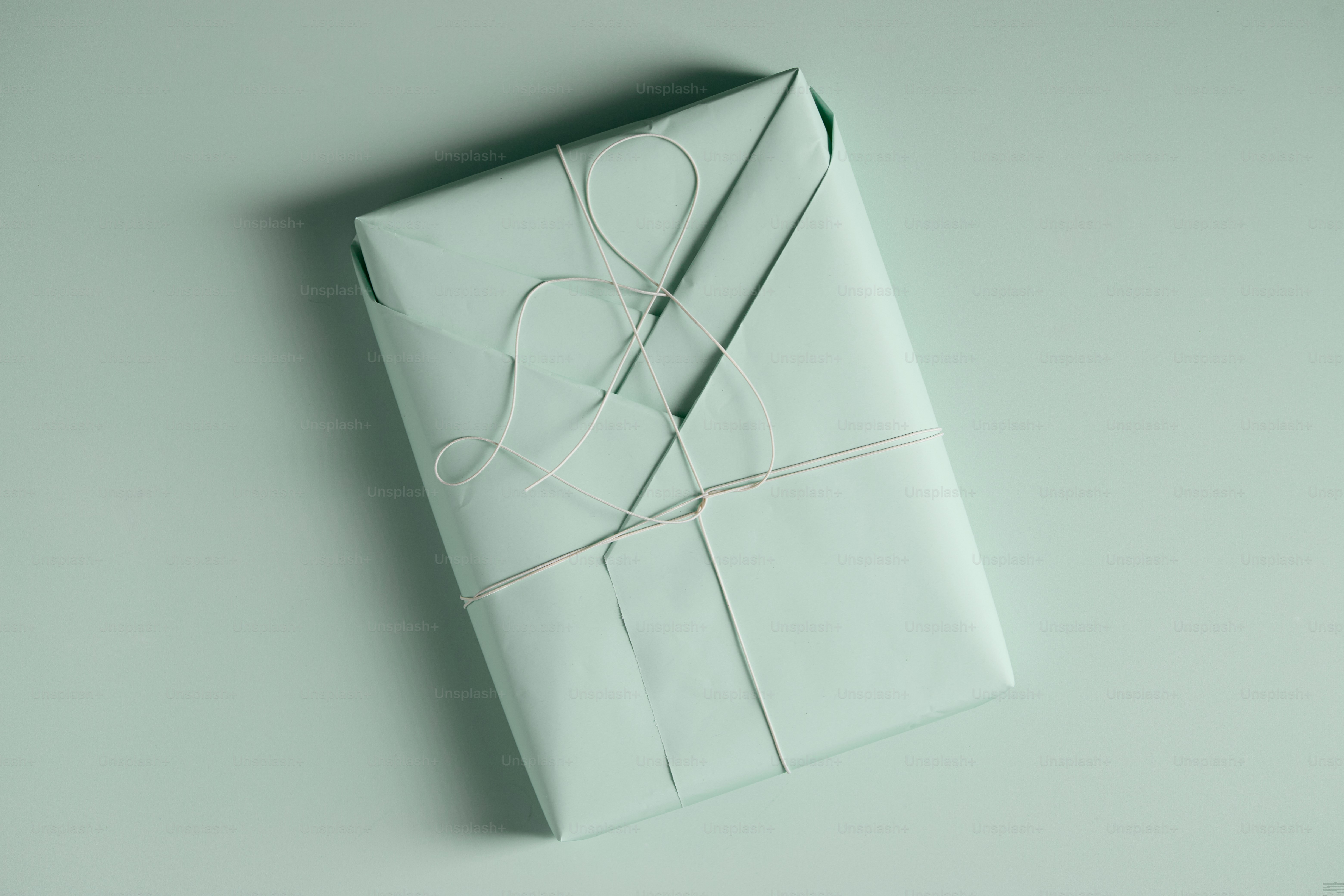 A gift wrapped in pale pink paper with string. photo – Gift Image on ...