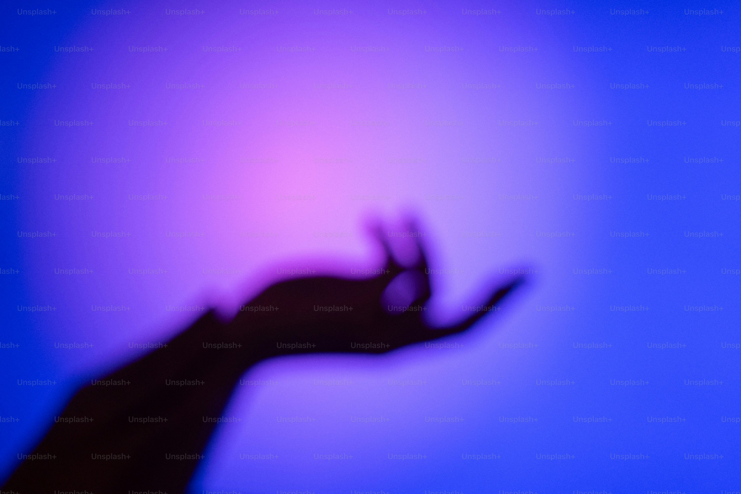 Silhouette of a hand reaching out against blue background photo ...