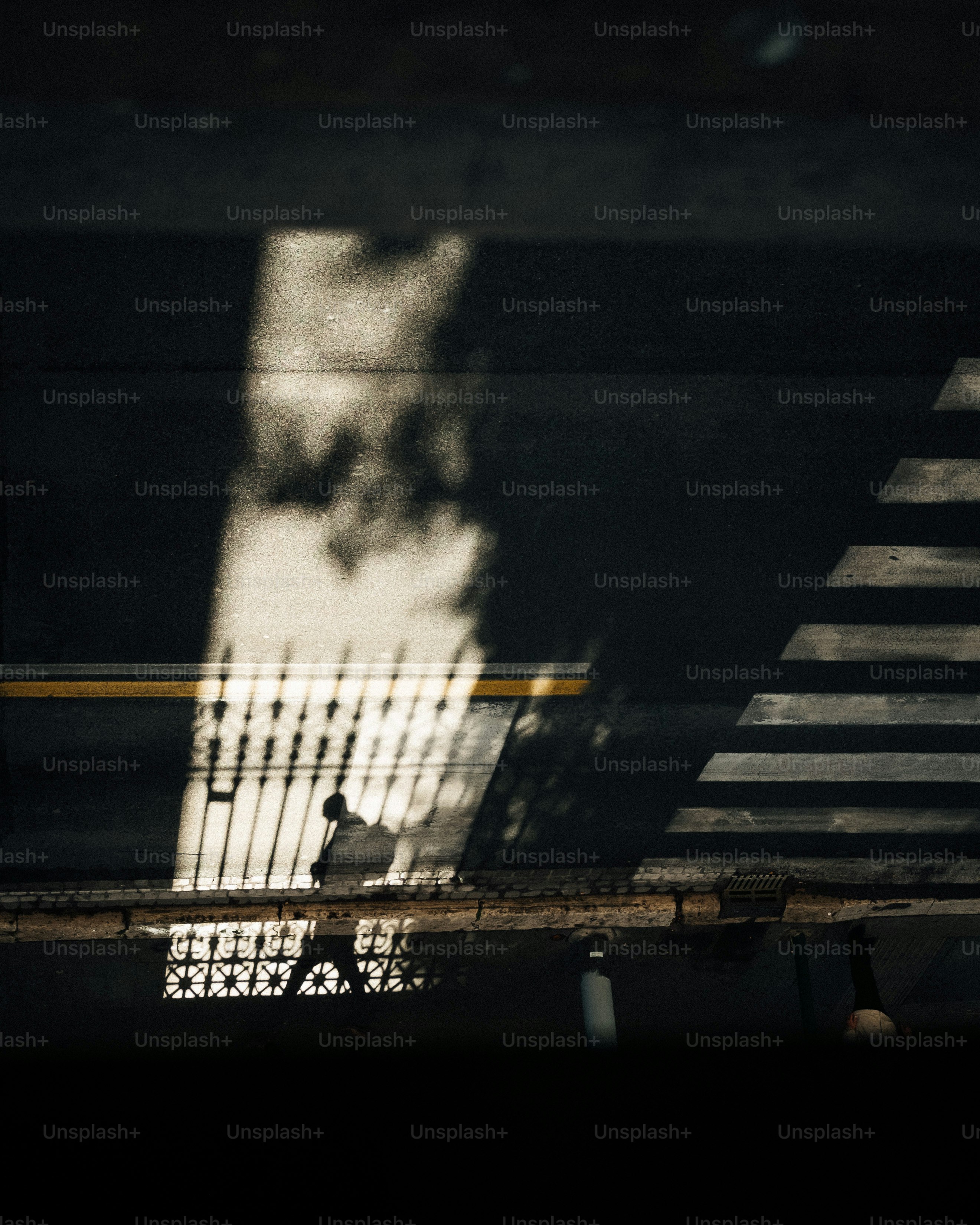A lone figure walks across a crosswalk in shadow. photo – Urban Image ...