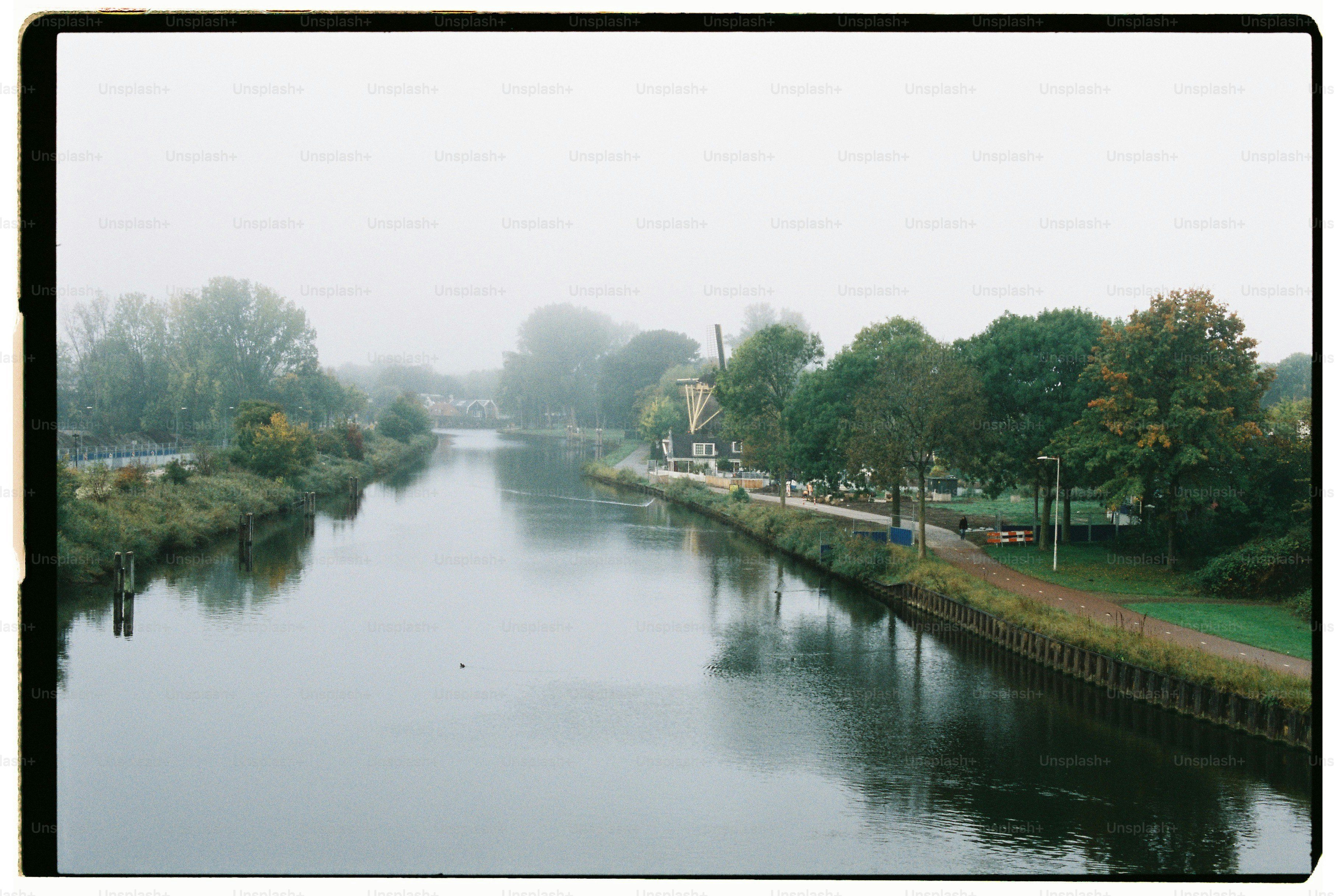 Misty river with trees and buildings along bank photo – Travel Image on ...