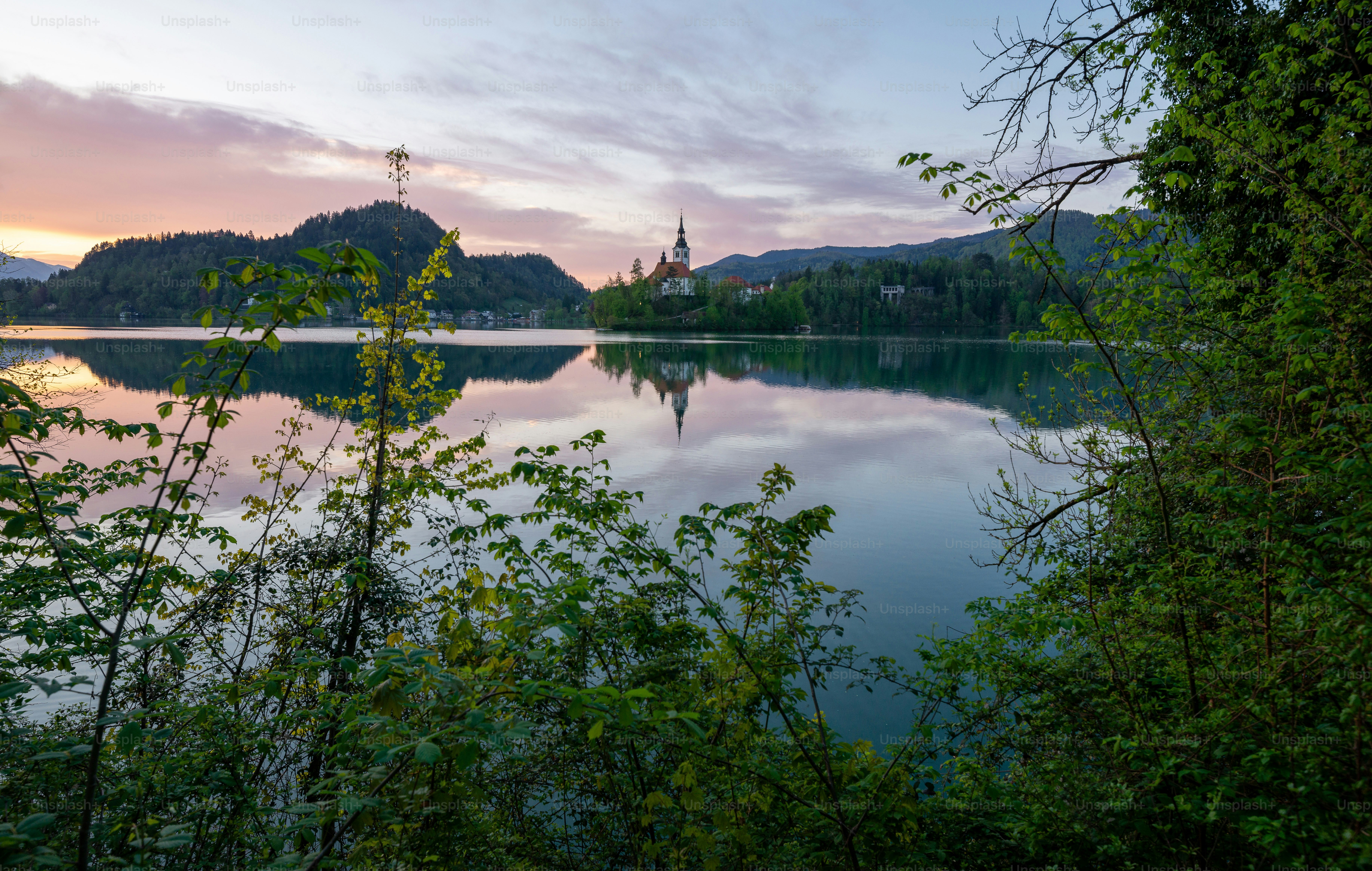 Island church on lake with mountains at sunset photo – Sunset Image on ...