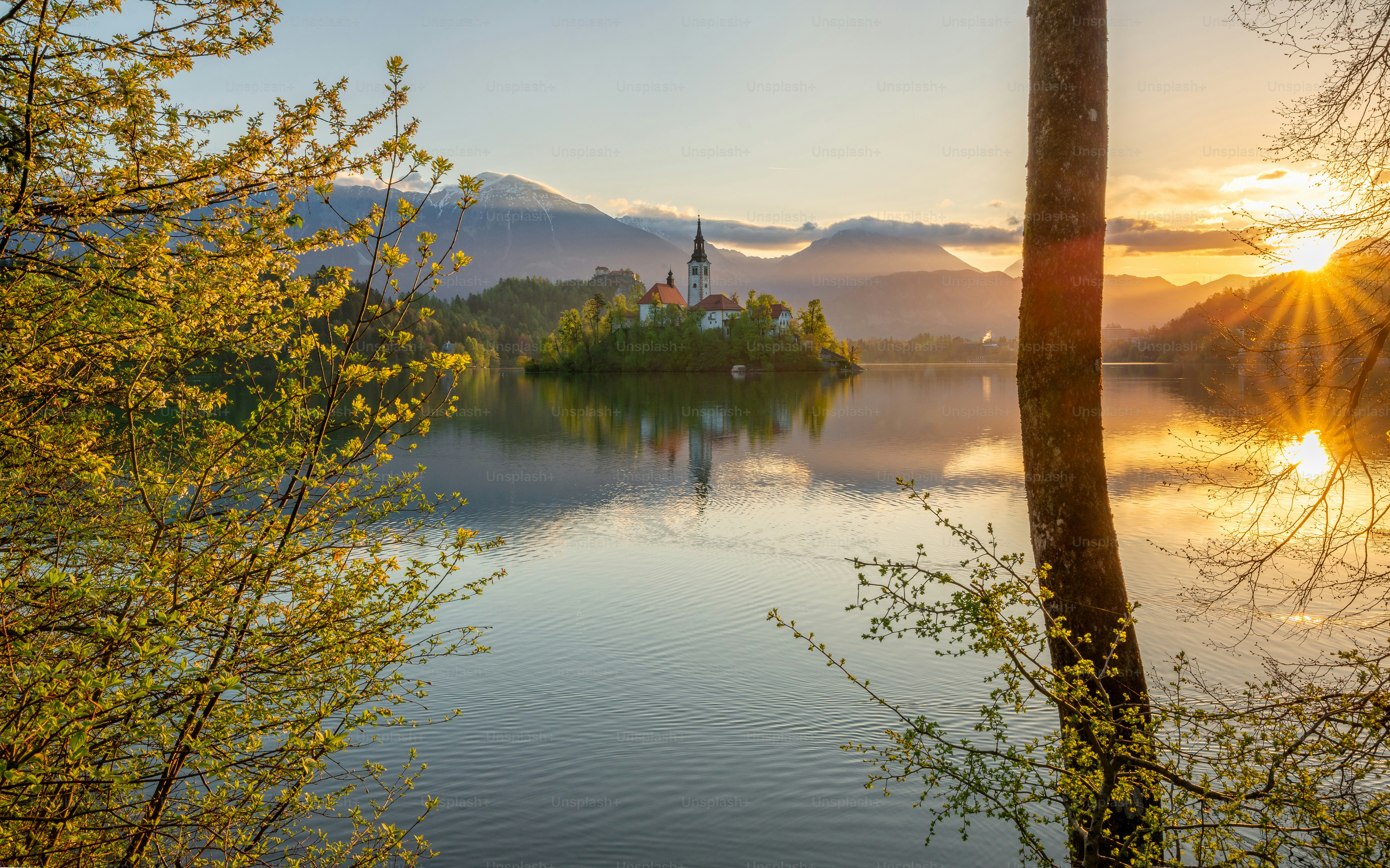 Island church on lake with mountains at sunset photo – Sunset Image on ...
