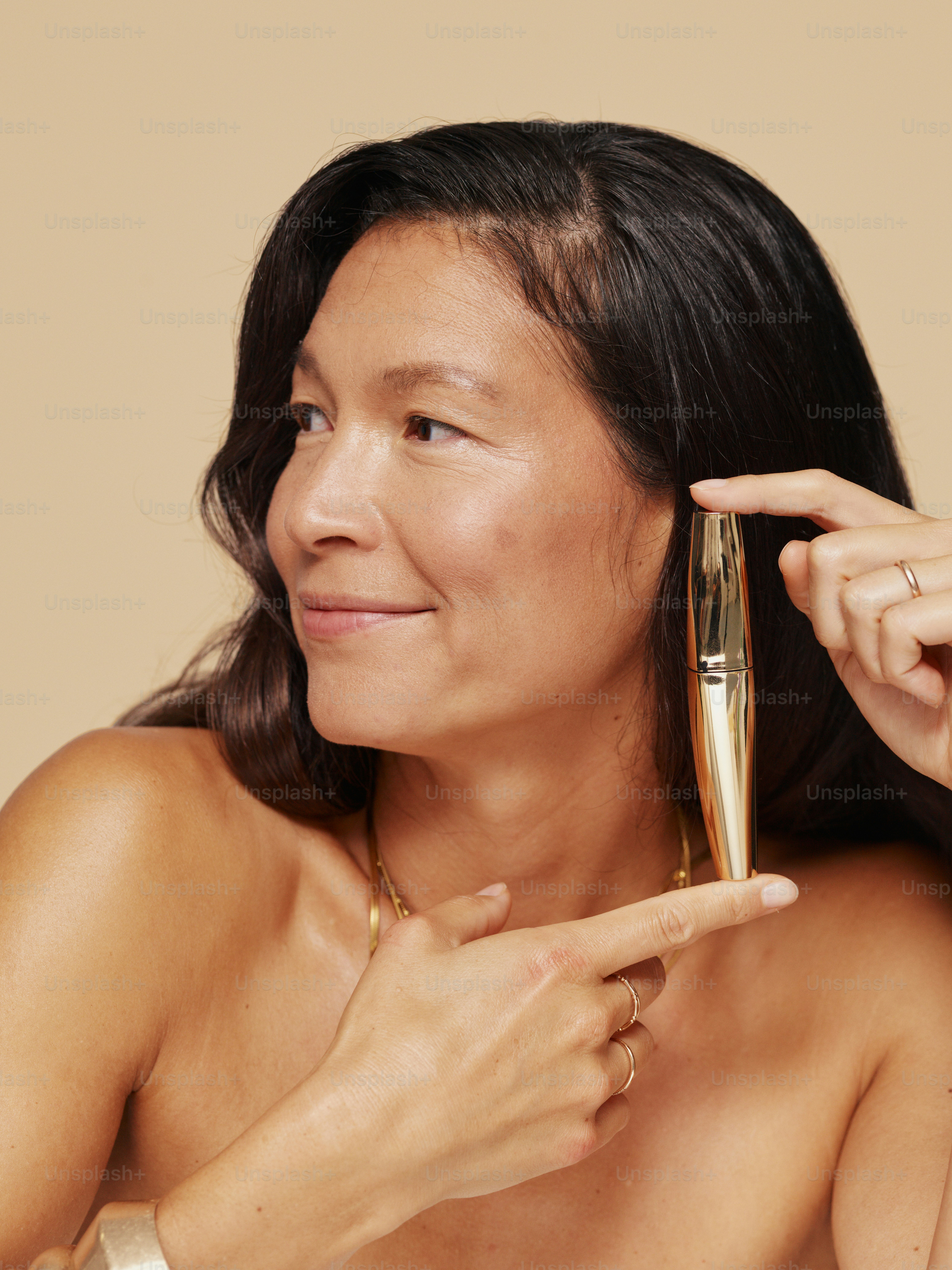 Woman holding a light green serum bottle near her shoulder photo ...