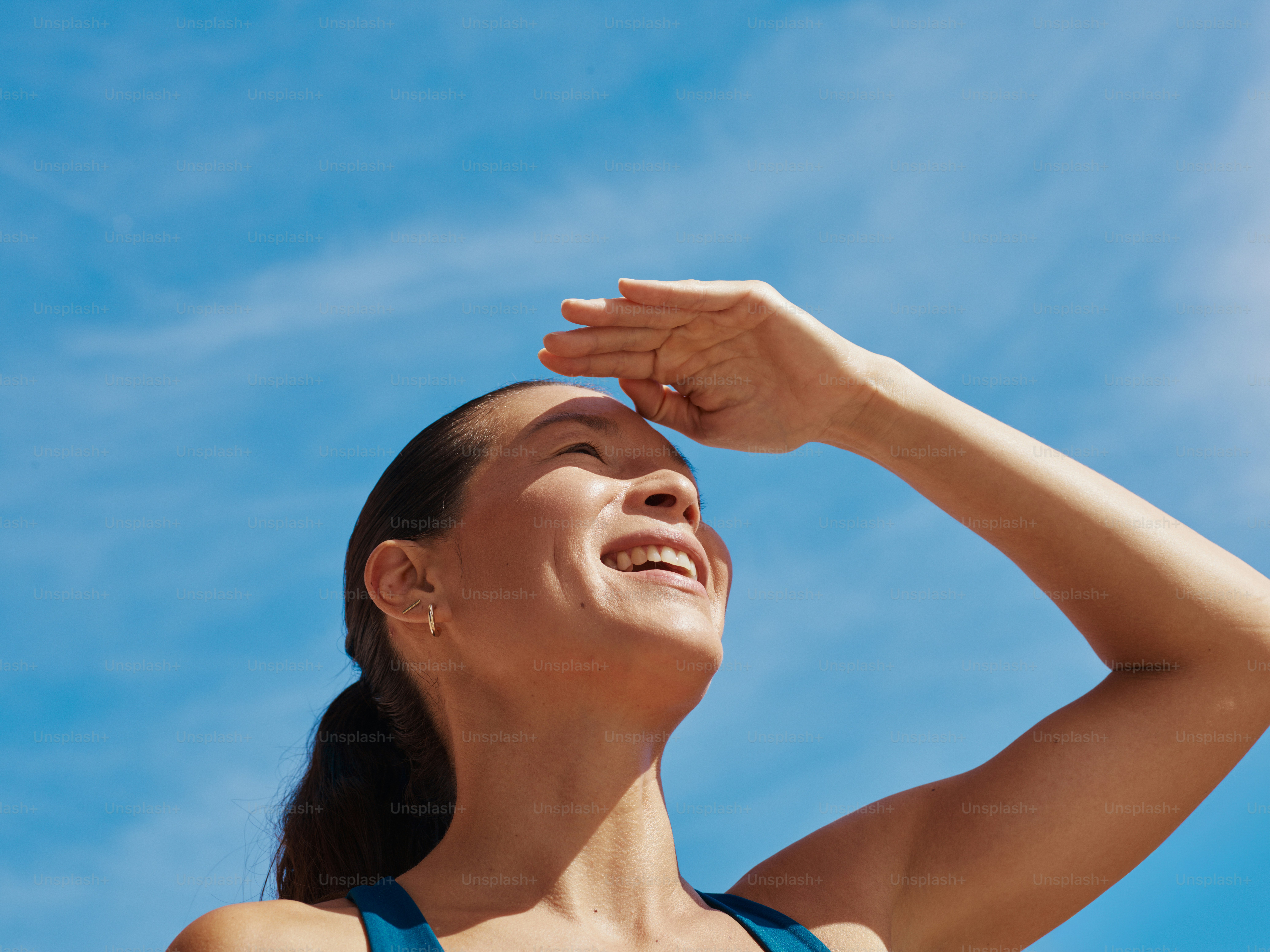 Woman shielding eyes from sun against blue sky photo – Clouds Image on ...