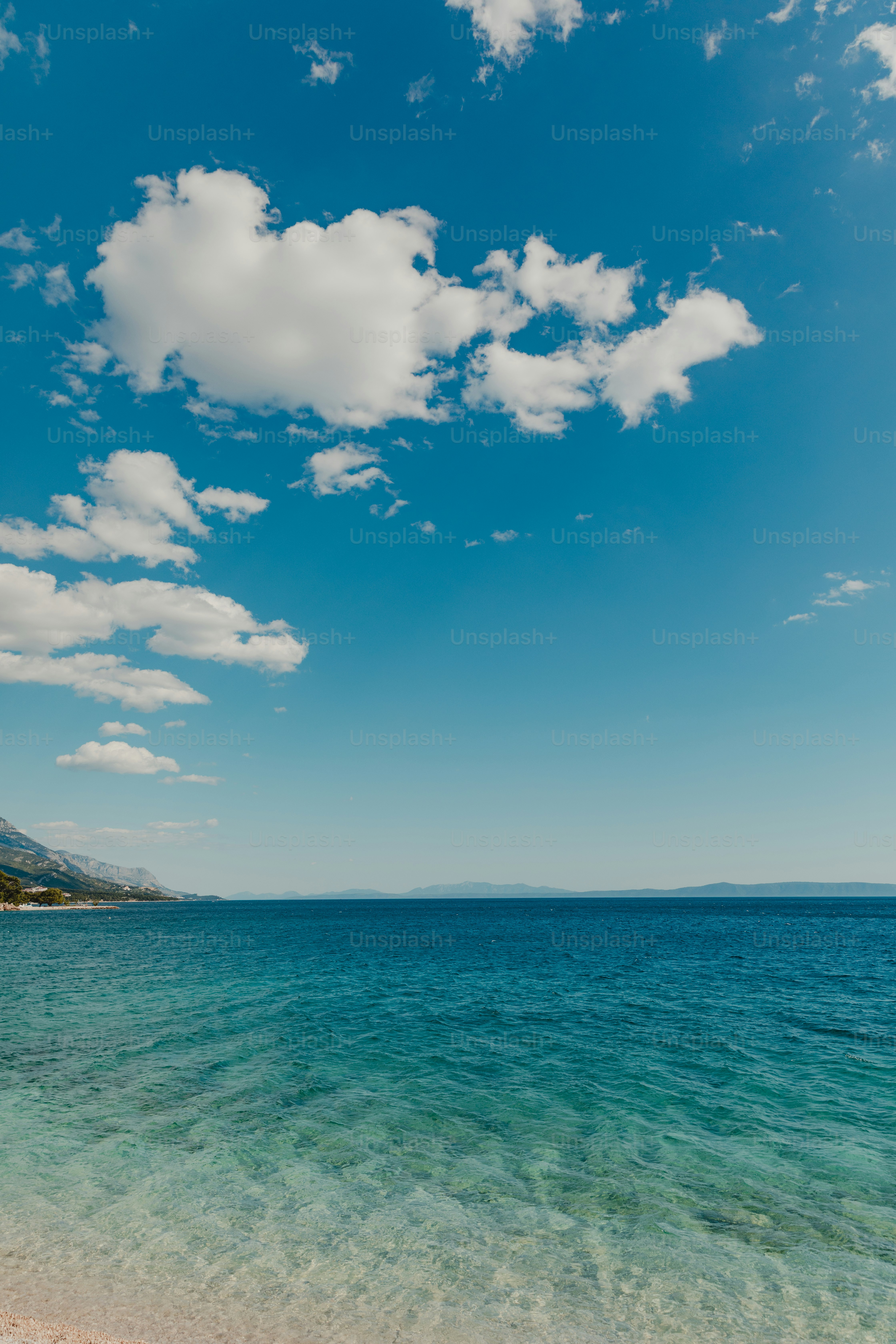 Clear blue ocean water under a sky with white clouds photo – Travel ...