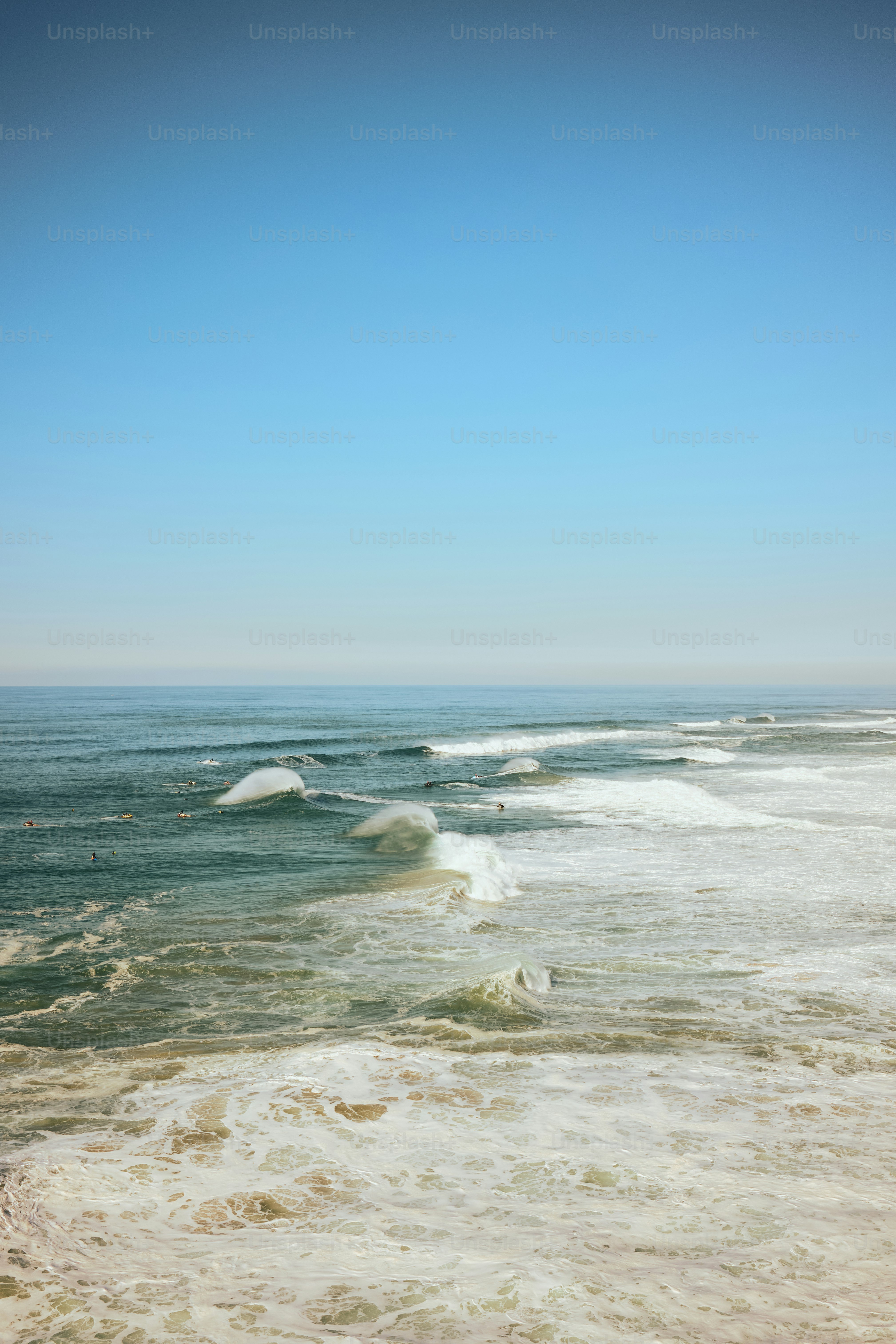 Olas rompiendo en una playa de arena bajo un cielo despejado foto ...