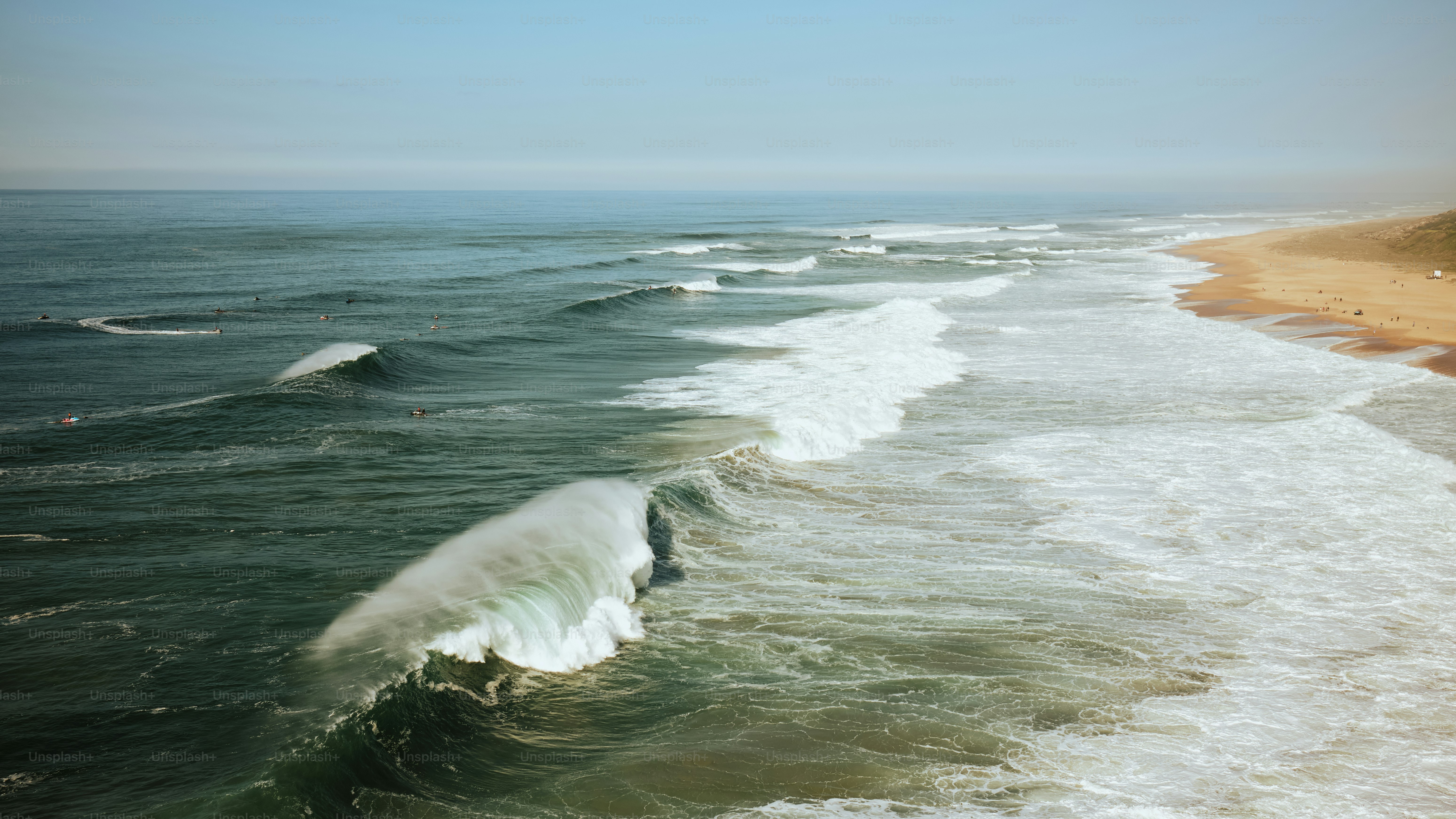 Olas rompiendo en una playa de arena bajo un cielo despejado foto ...