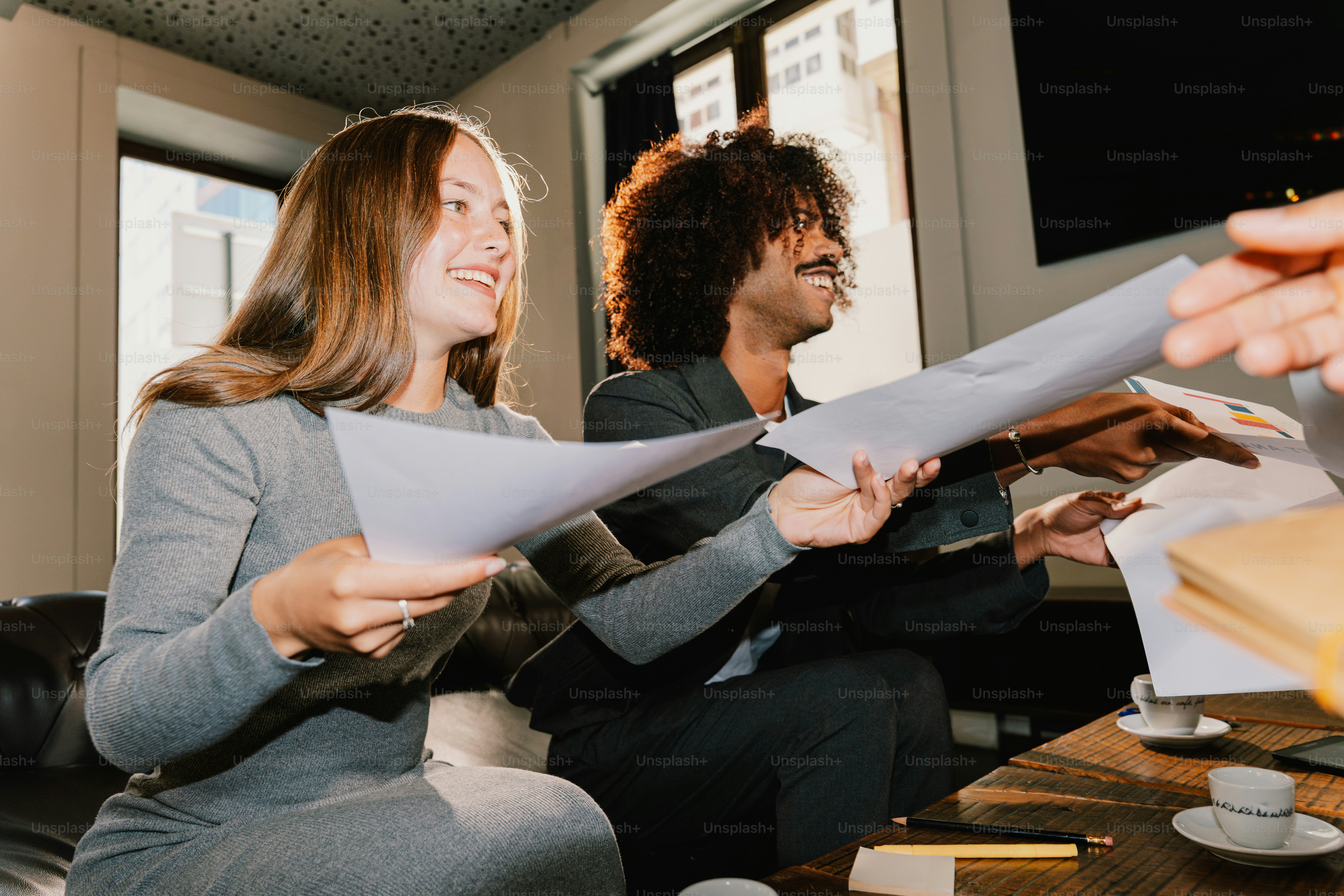 Two people passing documents in a meeting. photo – Image on Unsplash