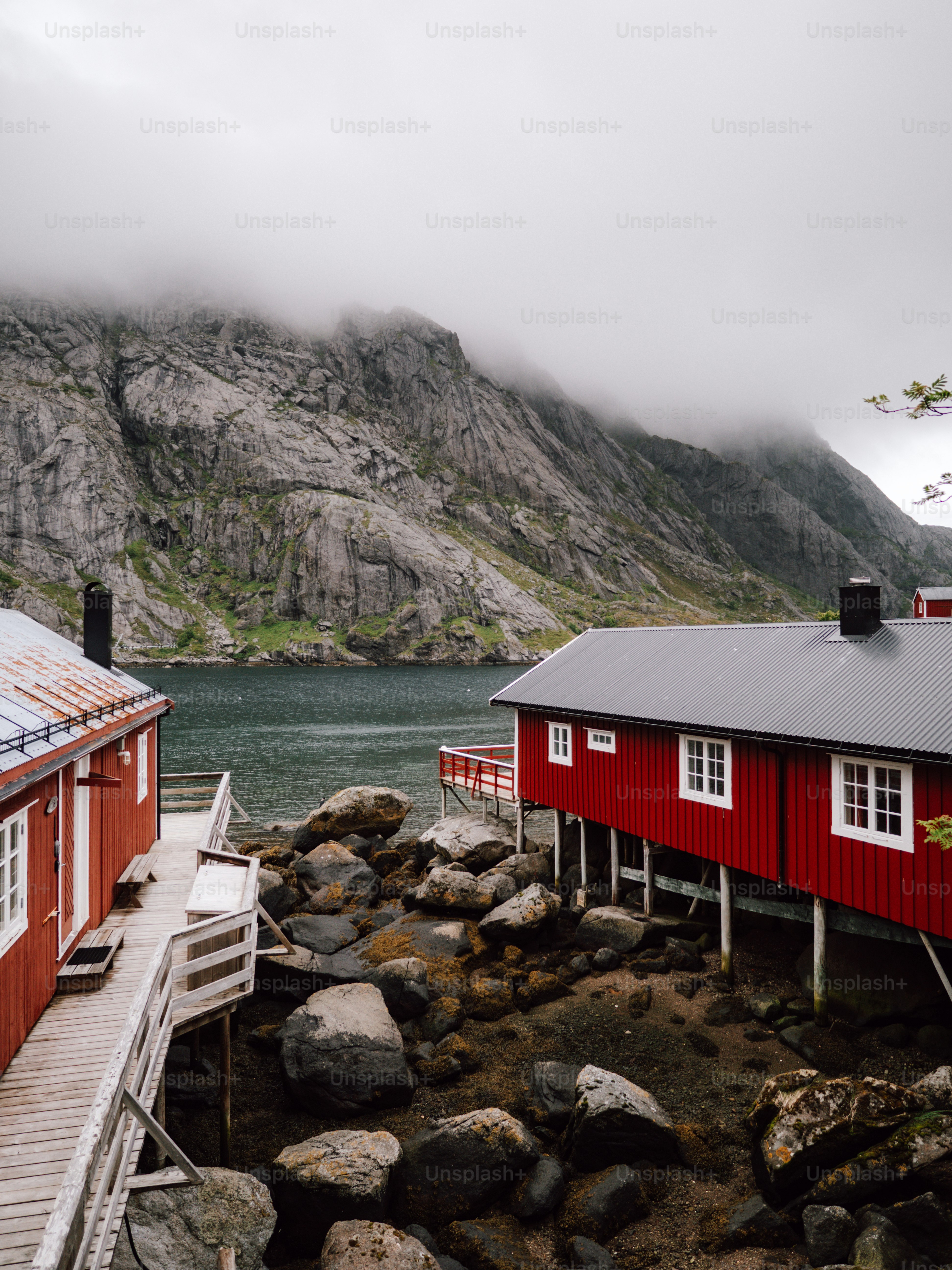 Red cabins on stilts by a rocky shore and mountains. photo – Norway ...