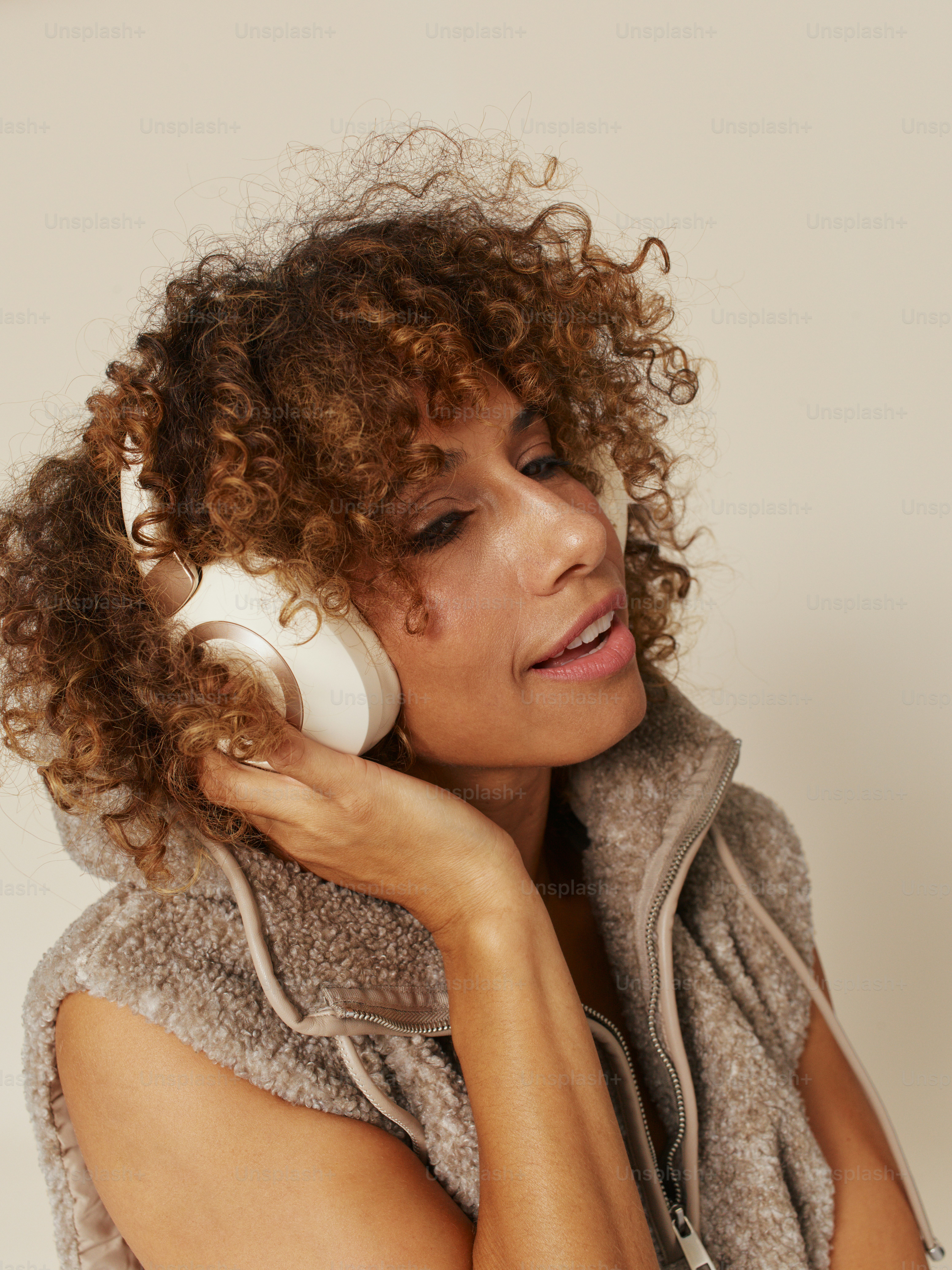 Woman with curly hair wearing headphones and vest photo – Portrait ...