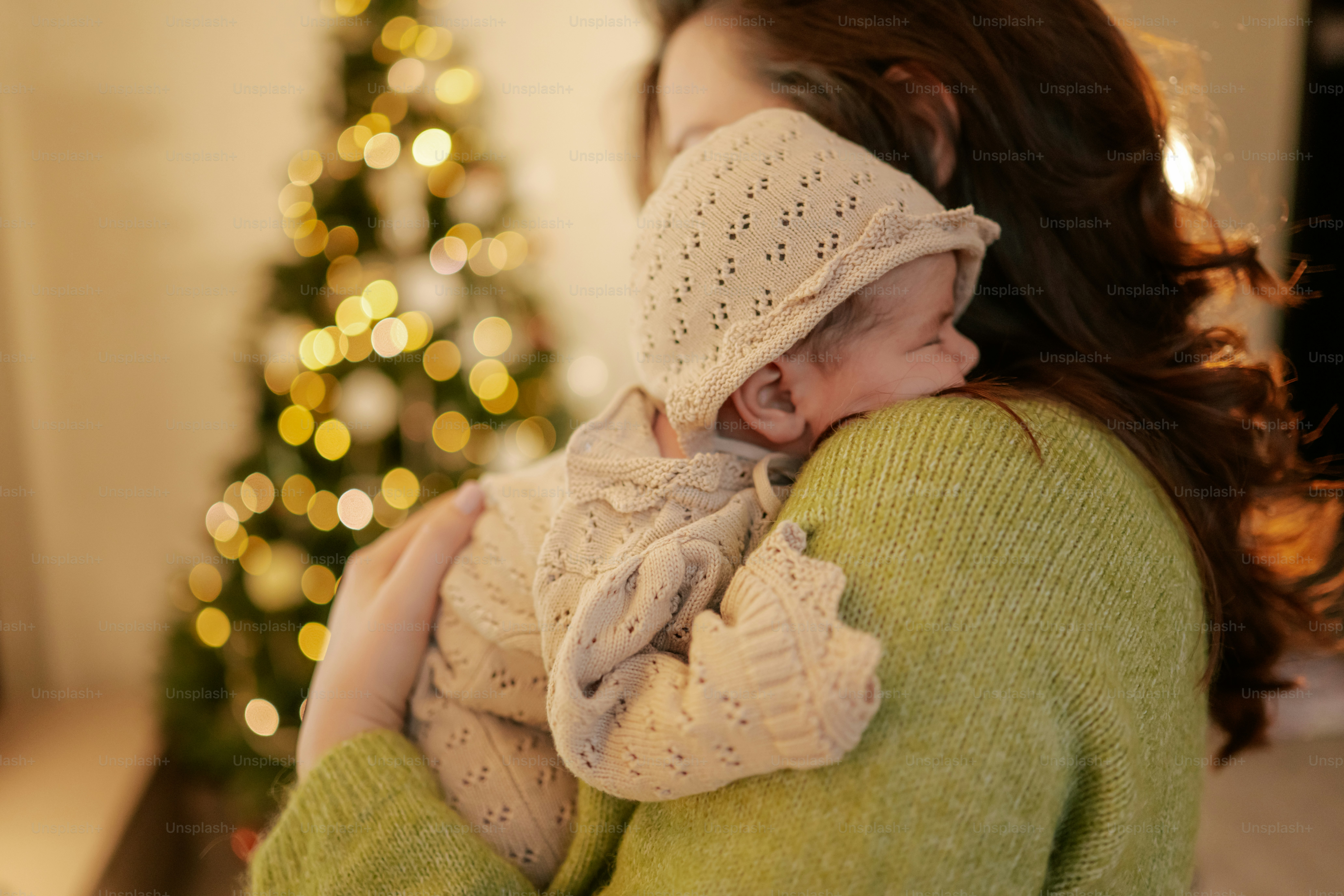 Mother holding a newborn baby with christmas tree lights. photo – Image ...