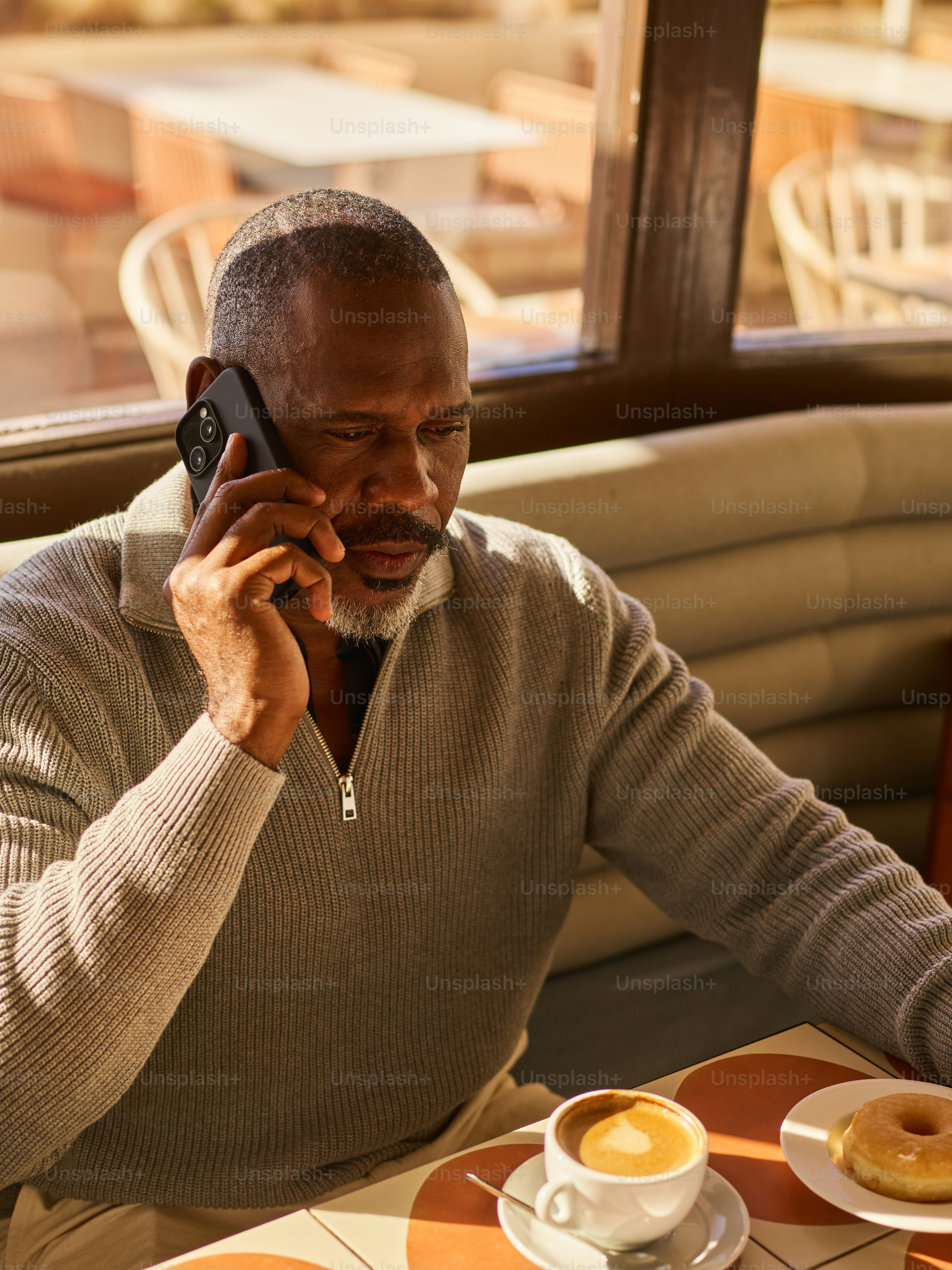 Un homme qui parle au téléphone à la table du café avec du café. photo ...