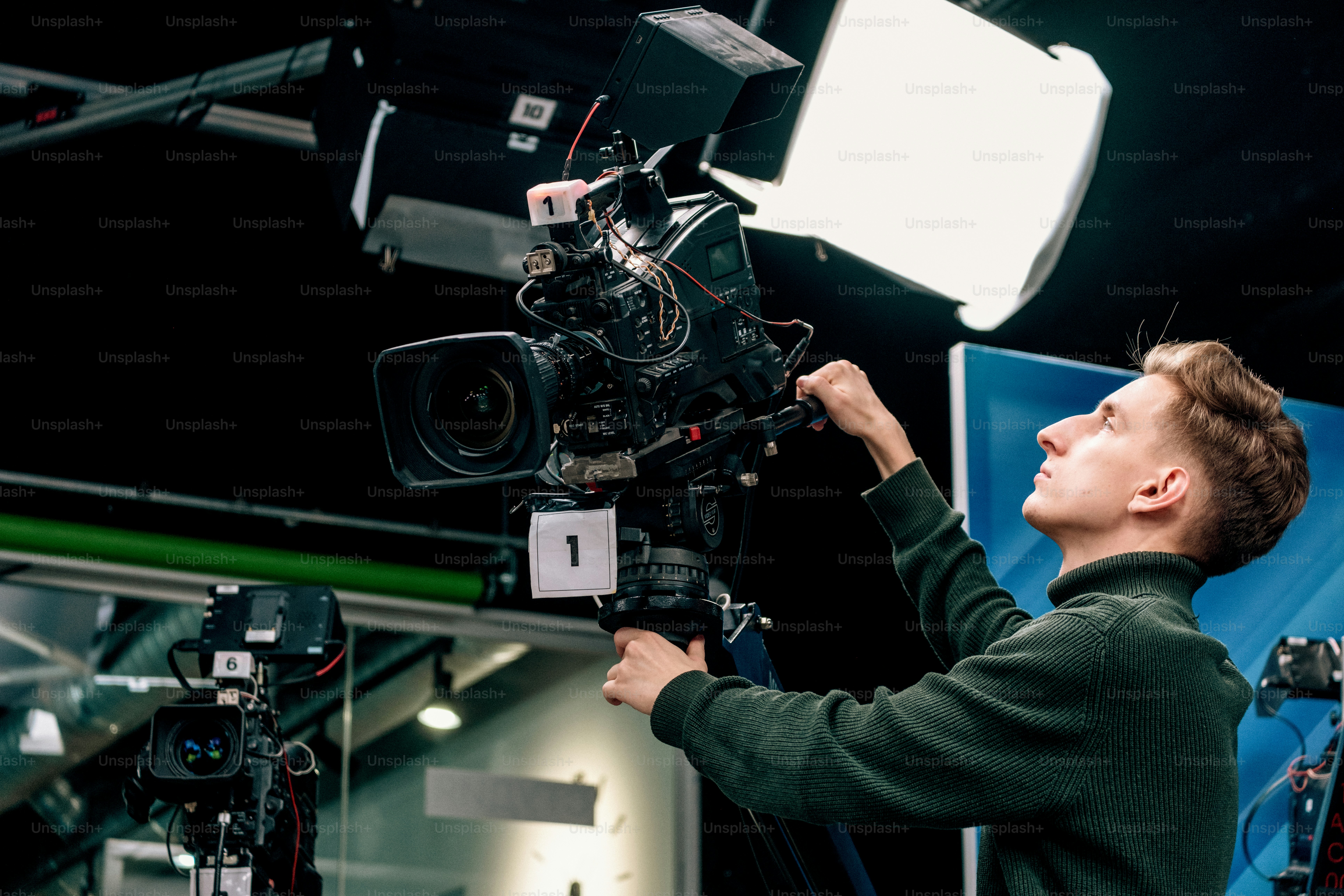 A man operating a professional video camera in a studio. photo – Camera ...