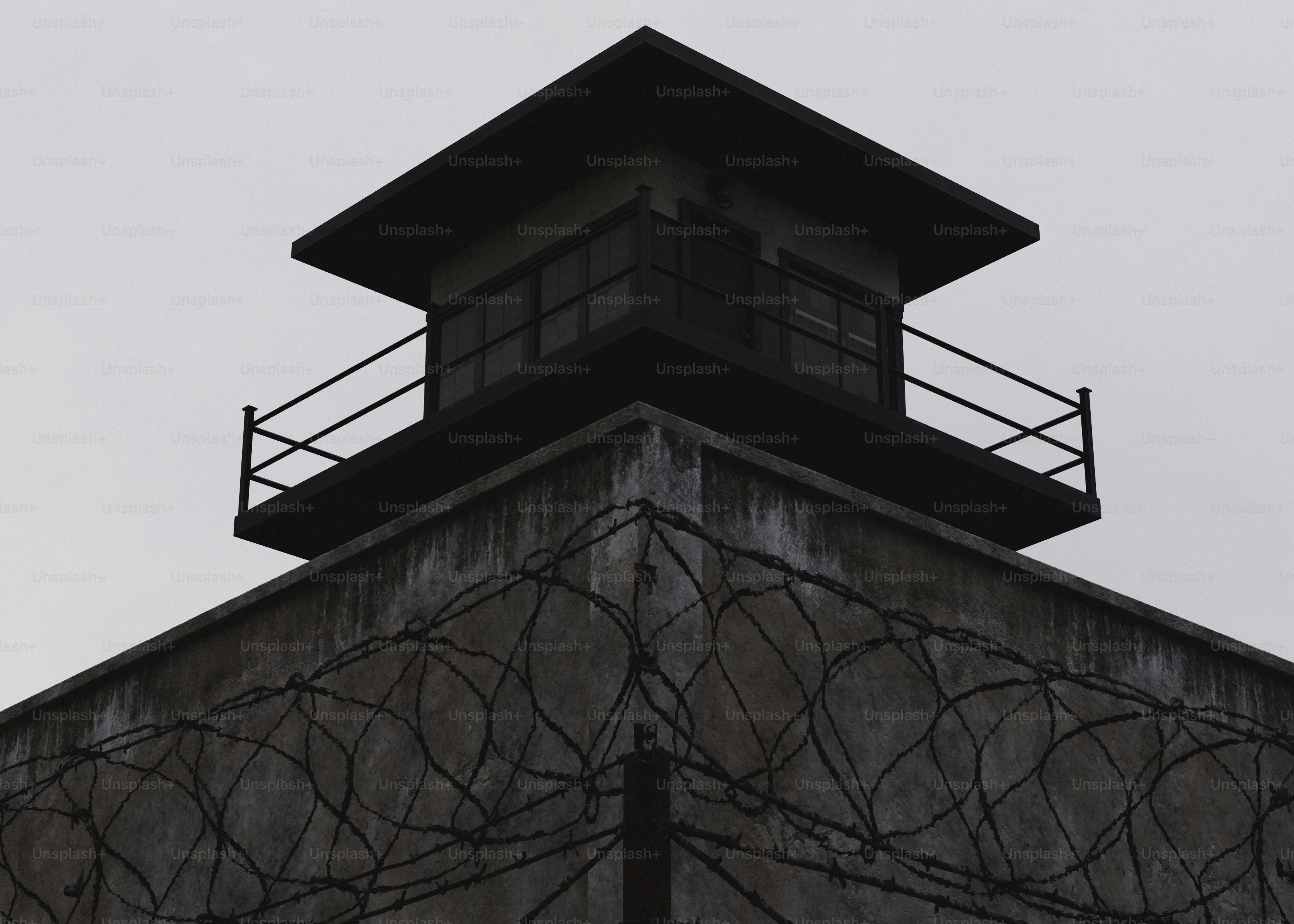 A dark prison watchtower with barbed wire. photo – Security Image on ...
