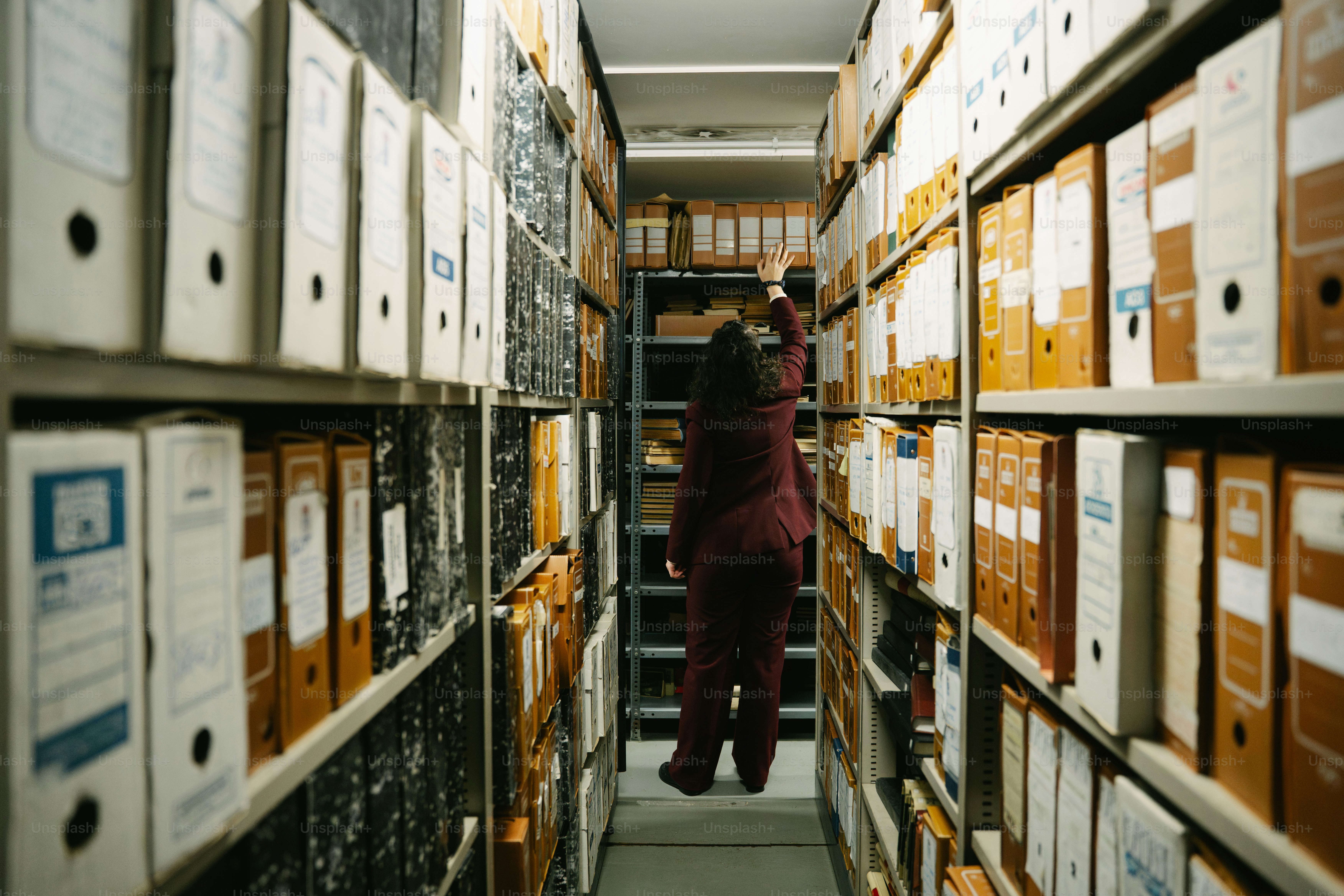 Woman reaching for file in archive storage room photo – Library Image ...