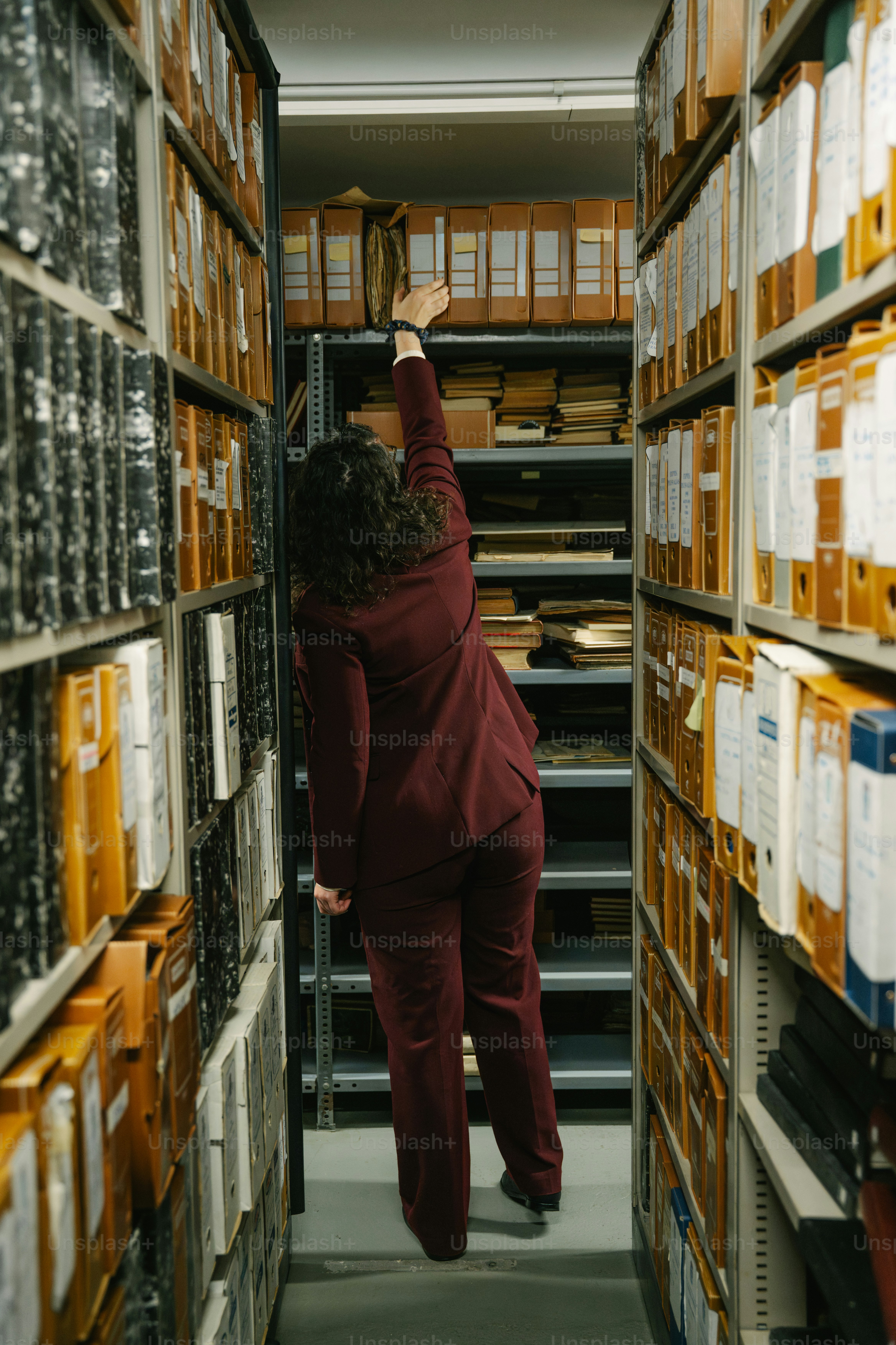 Woman reaching for file in archive storage room photo – Library Image ...